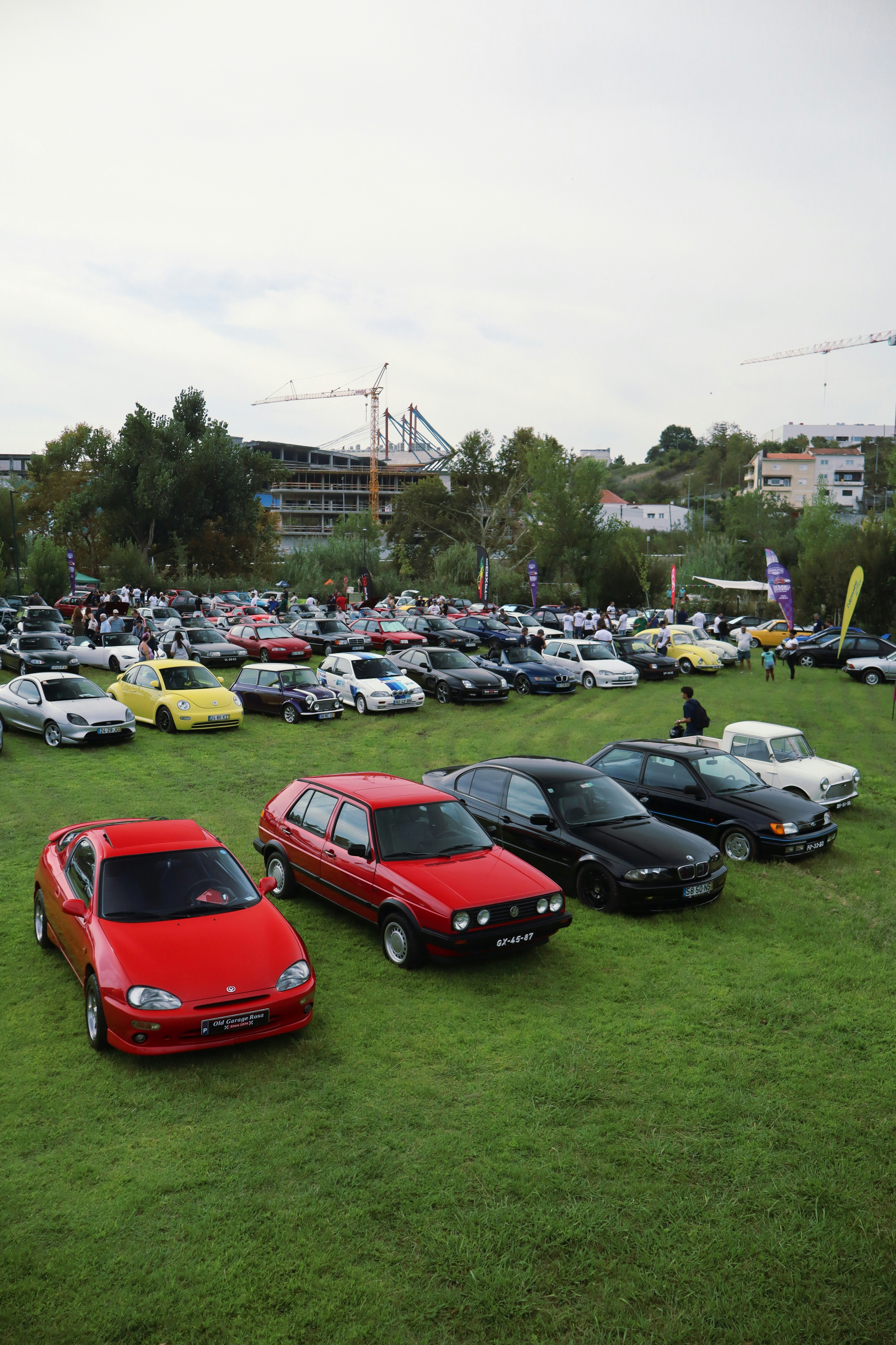 Car Show on the Emerald Field: A Row of Vibrant Hues Among Casual Spectators