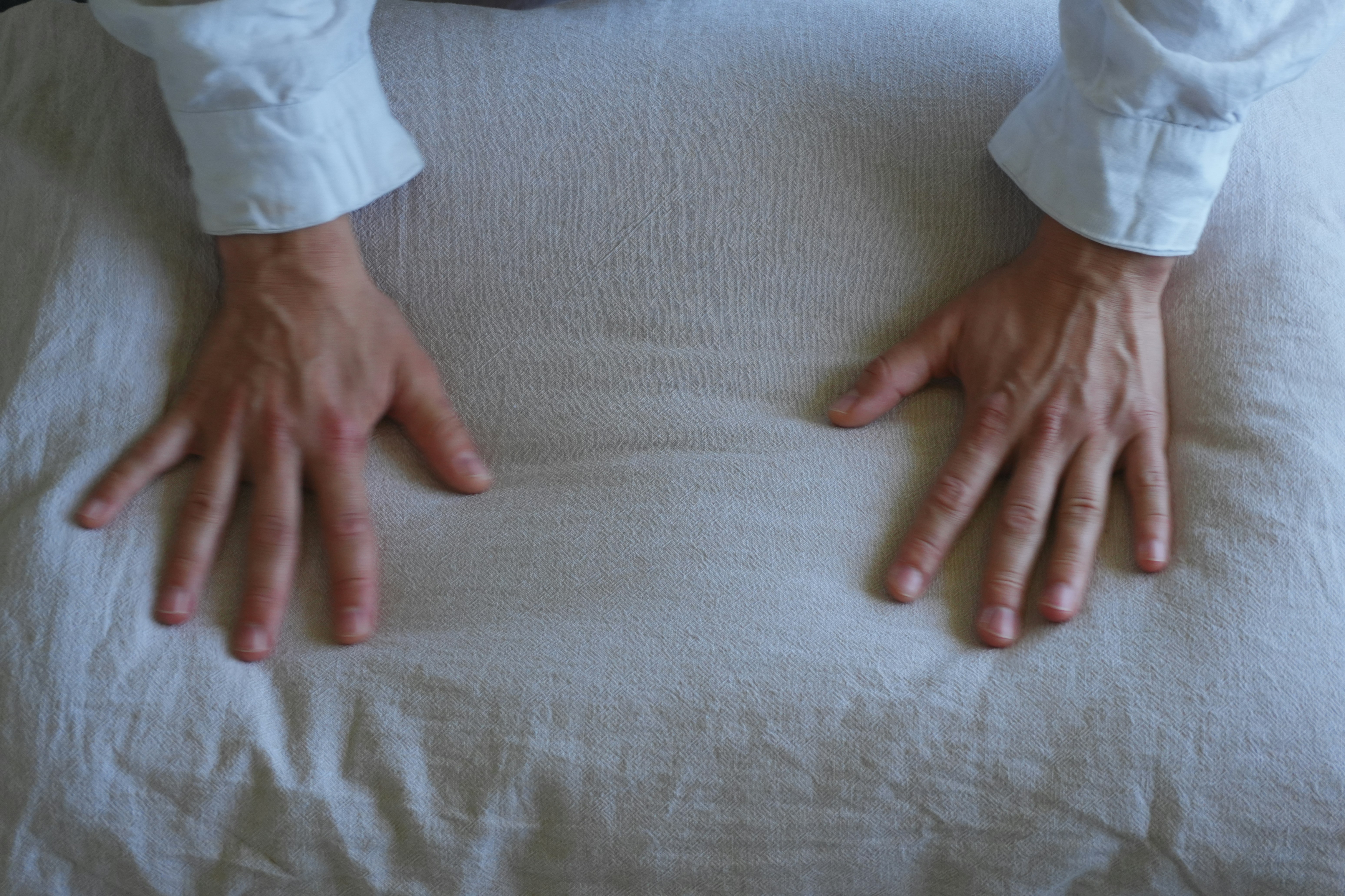 Hands on Linen: Quiet Tension on a Bed-sheet