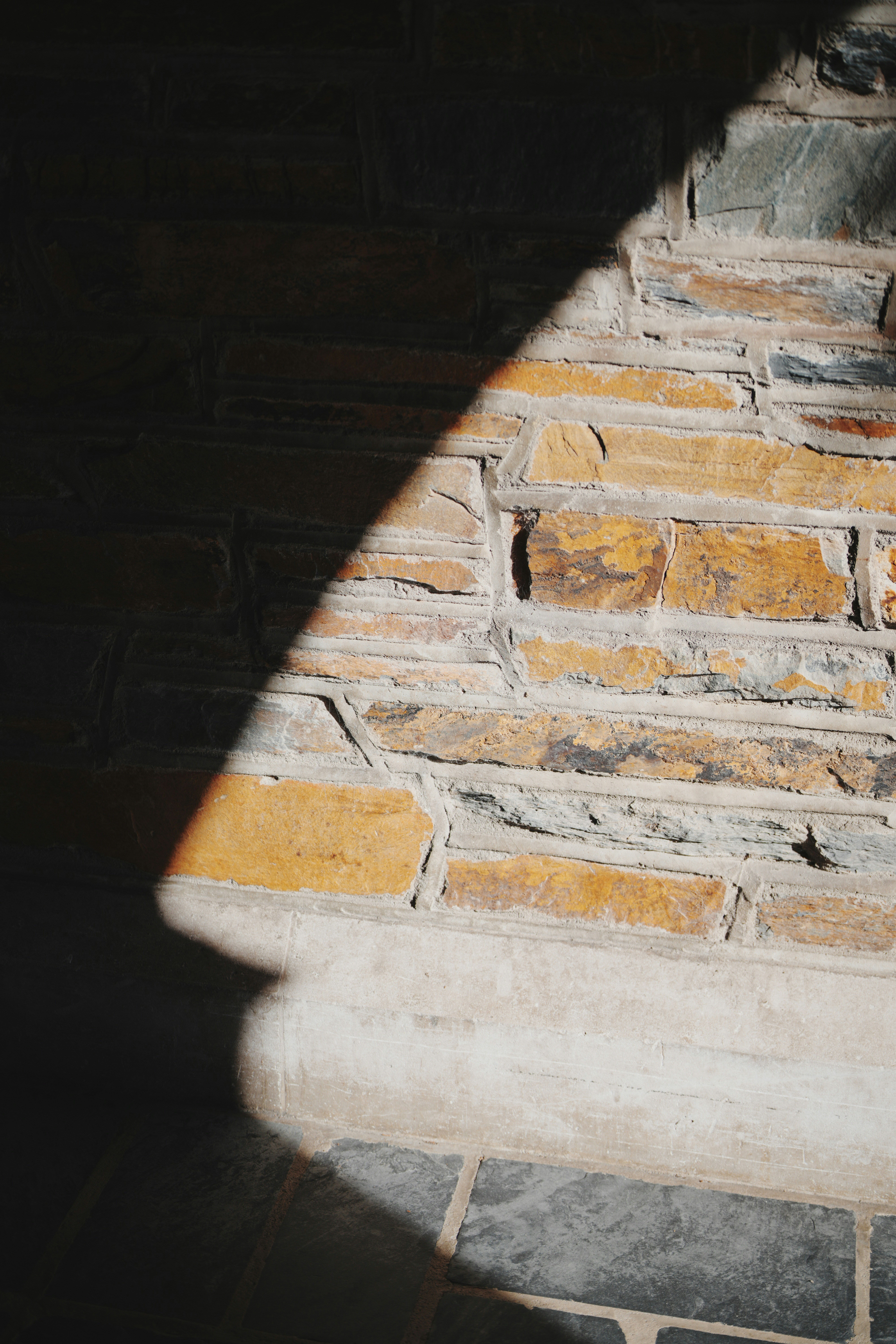 Shadowed Corner: Sunlit Brick Wall Amid Diagonal Shade