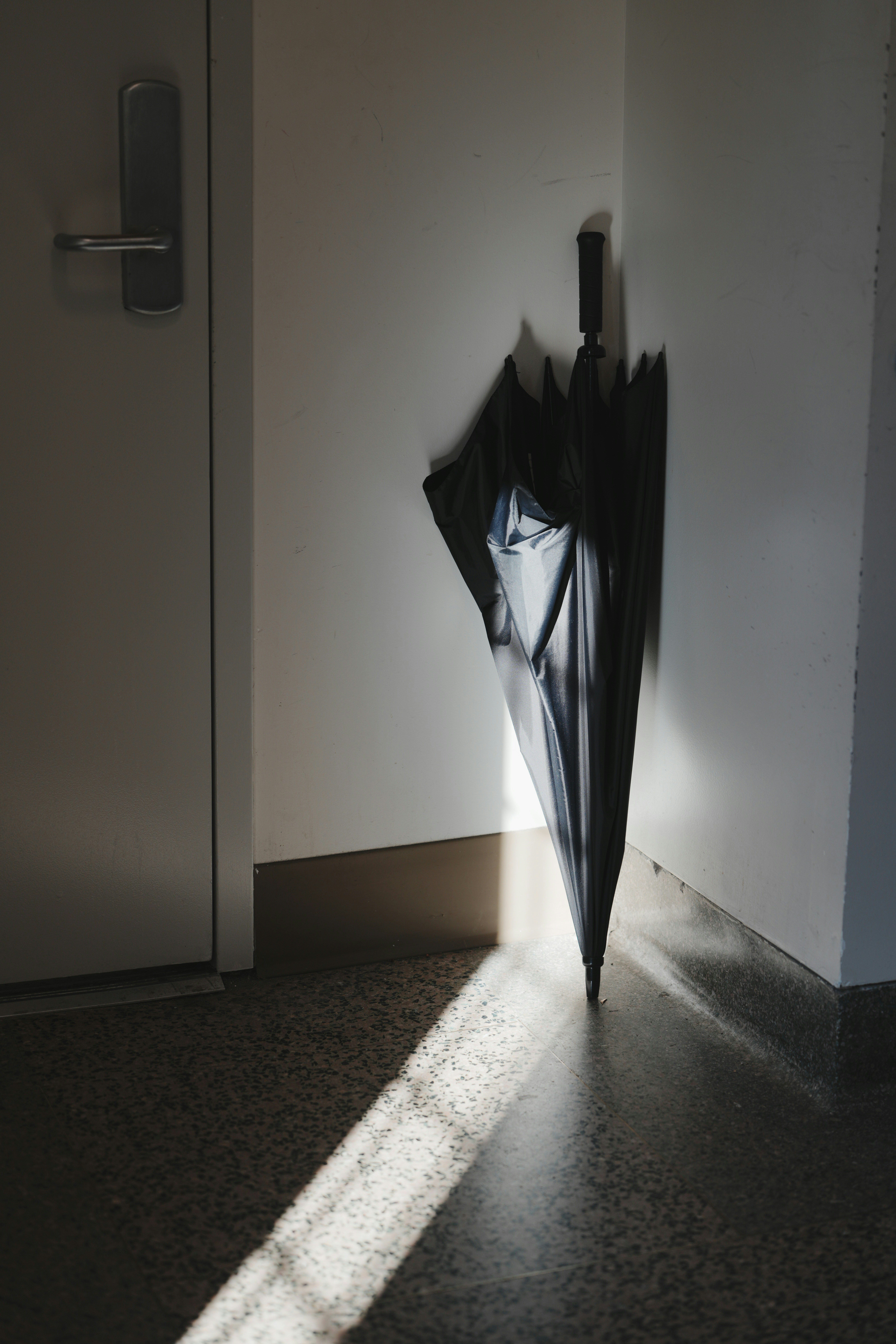 Shade in the Corner: A Closed Umbrella Leaning into Light