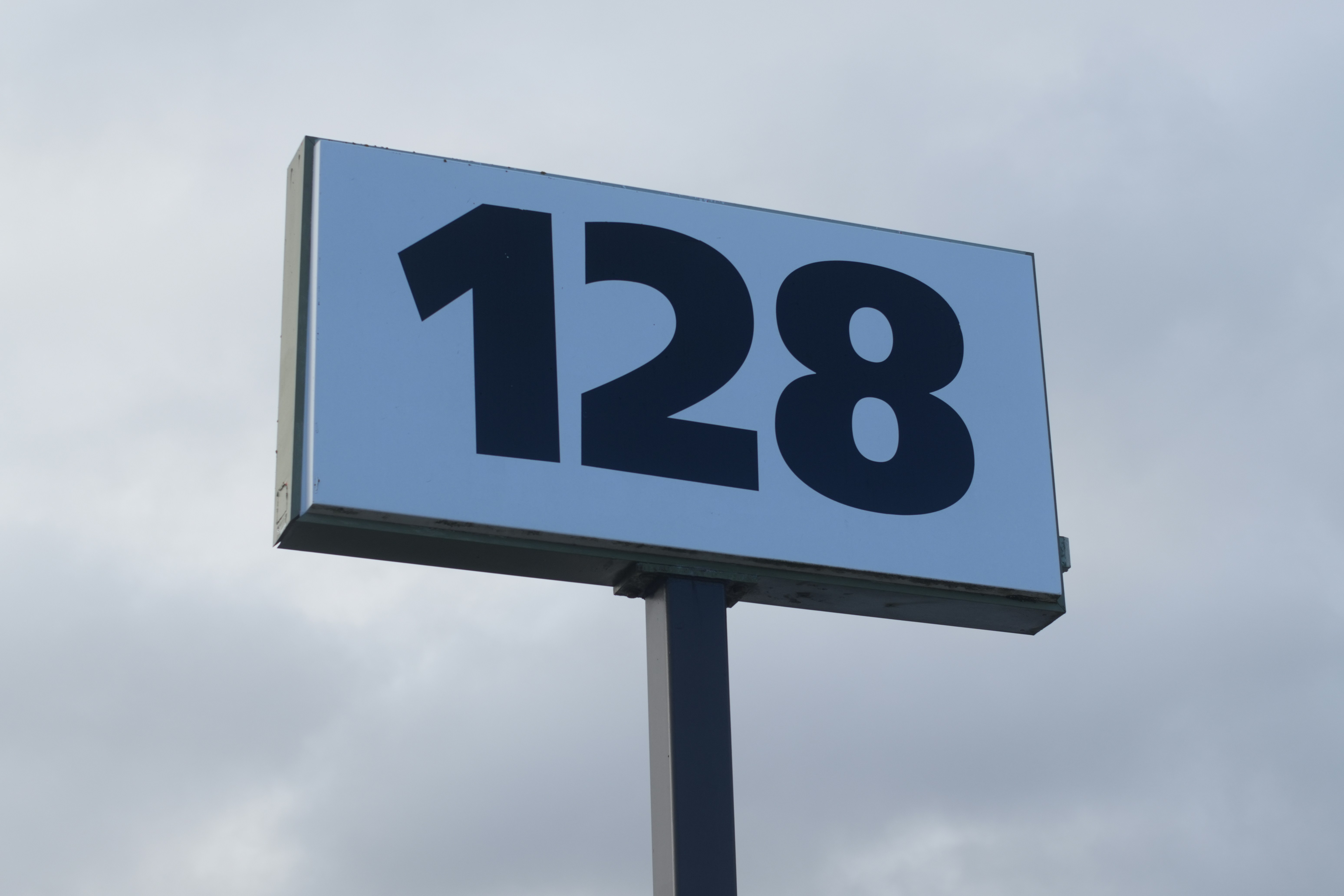 Bold Blue Sign: The Number 128 Rising Above a Quiet Sky