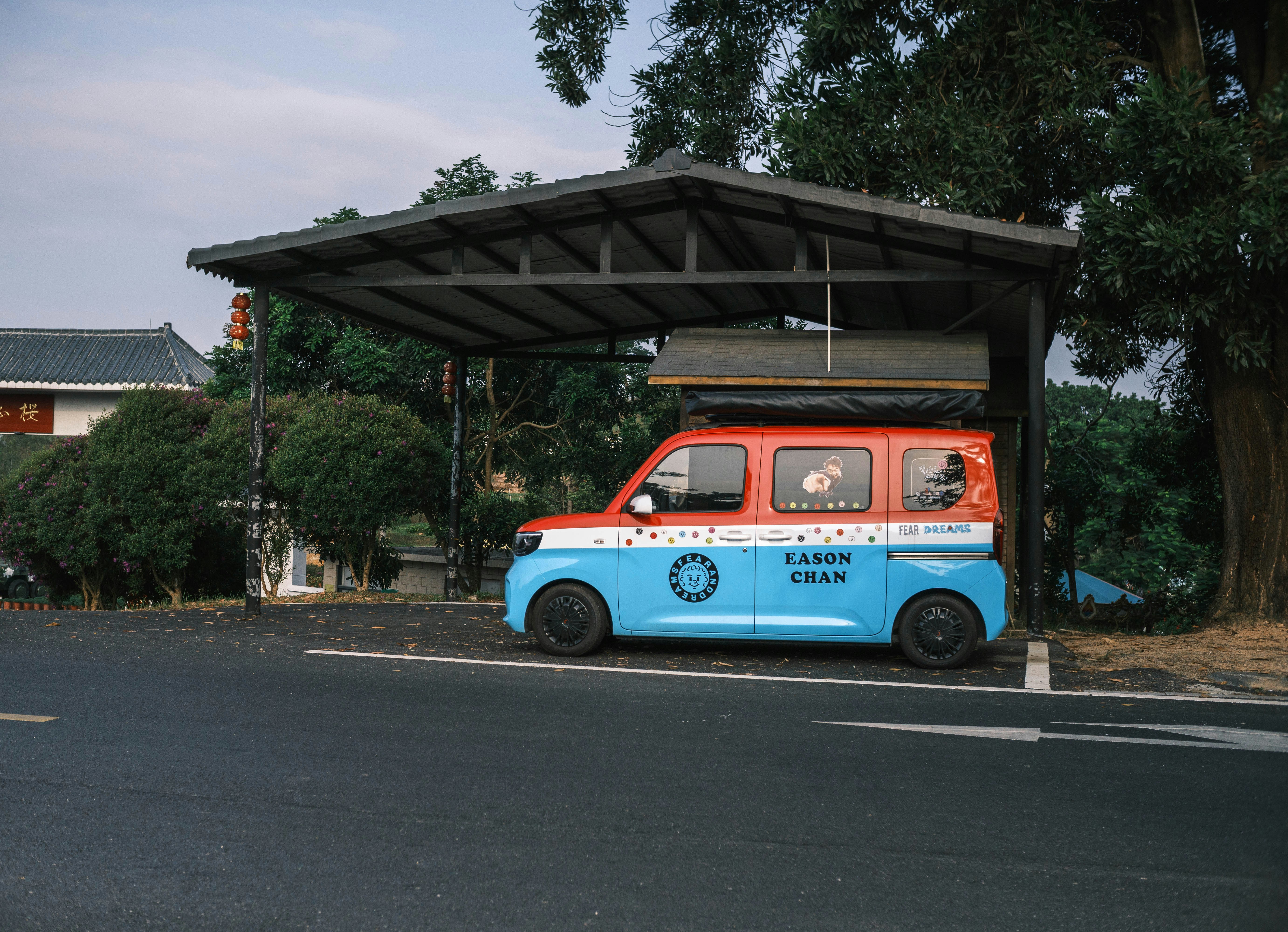 Colorful vintage van under a shelter, parked along a quiet road