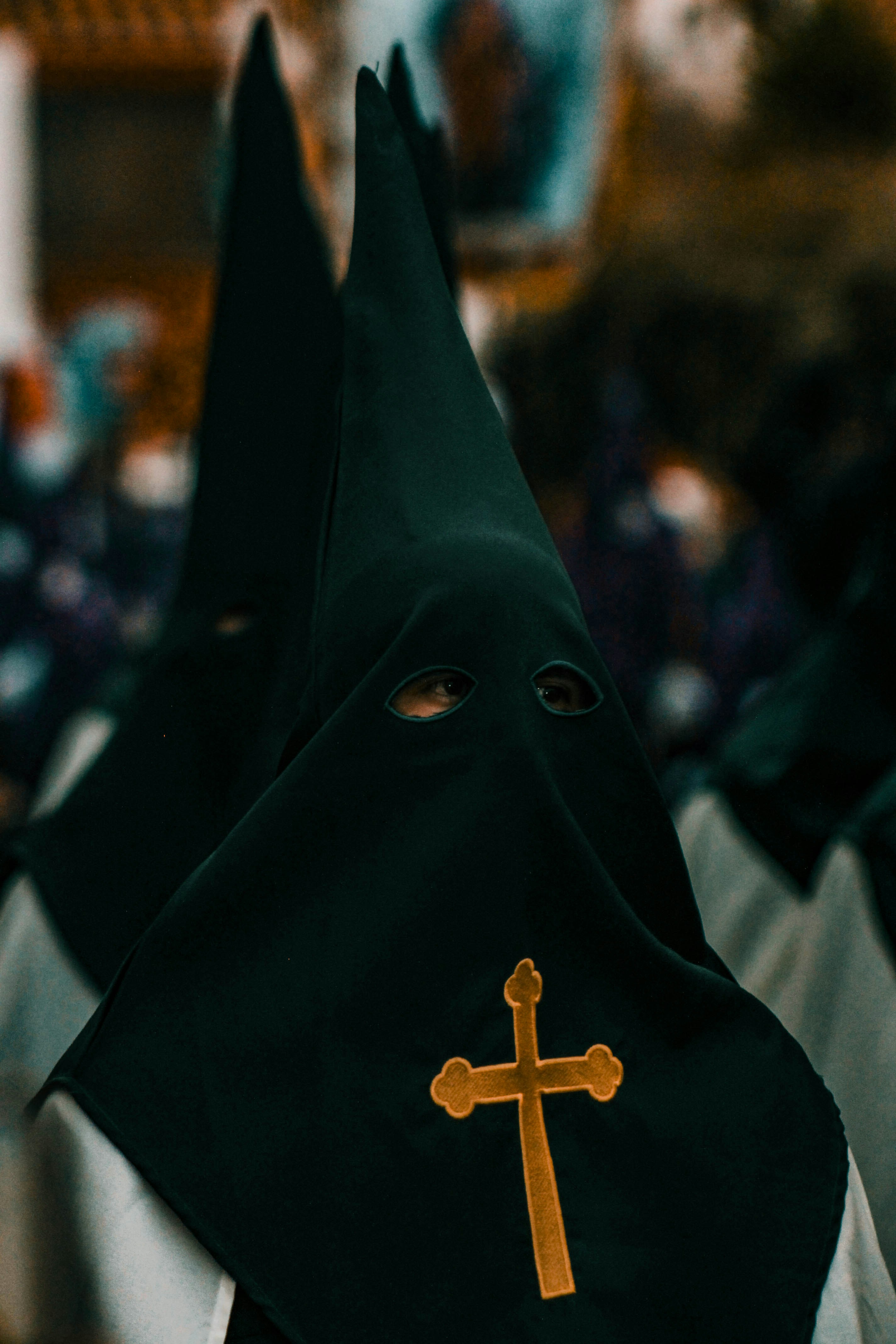Veiled Witness: A hooded figure with a golden cross amid vigil lights