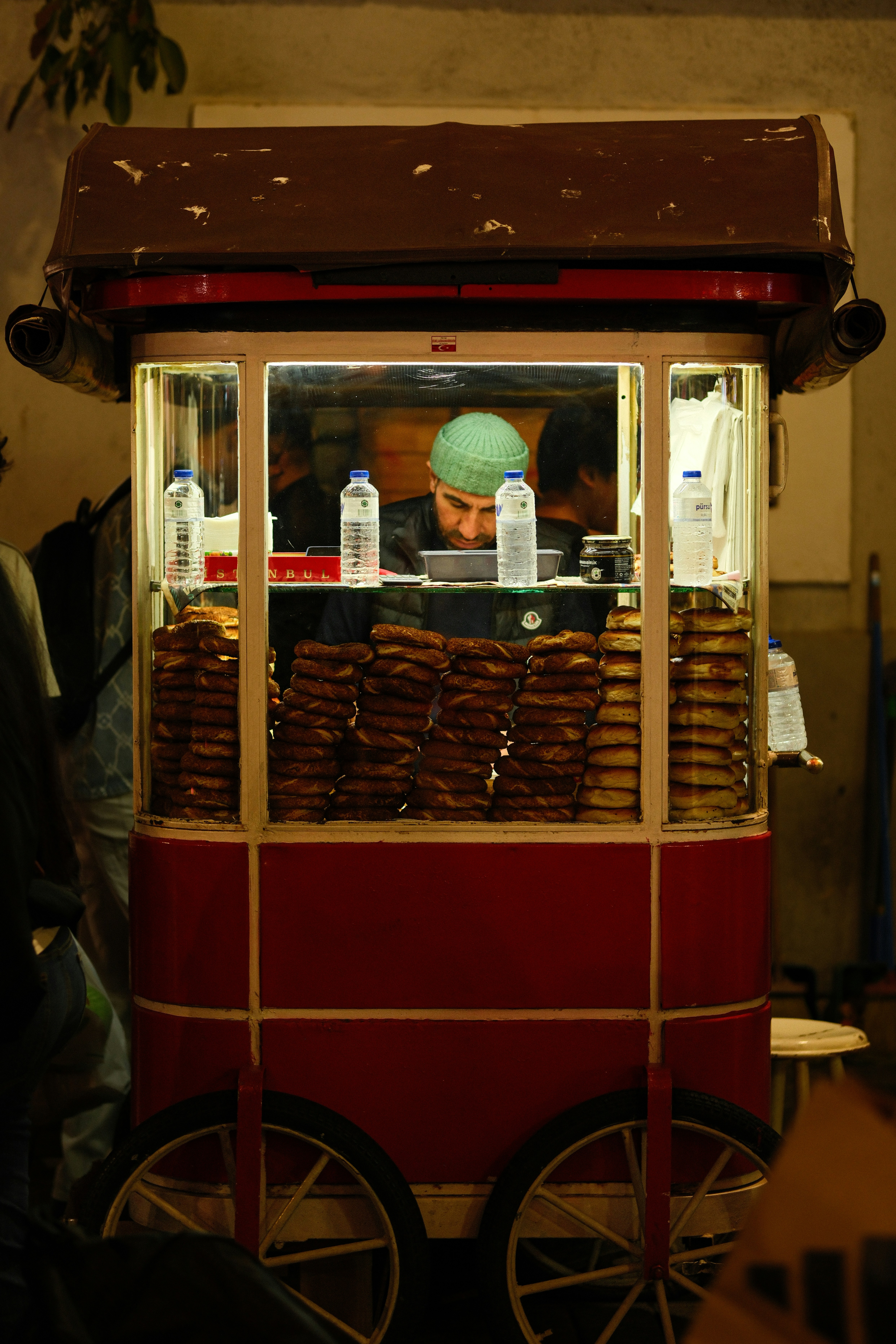 Stacked Treats and a Watchful Vendor in a Red Street Cart