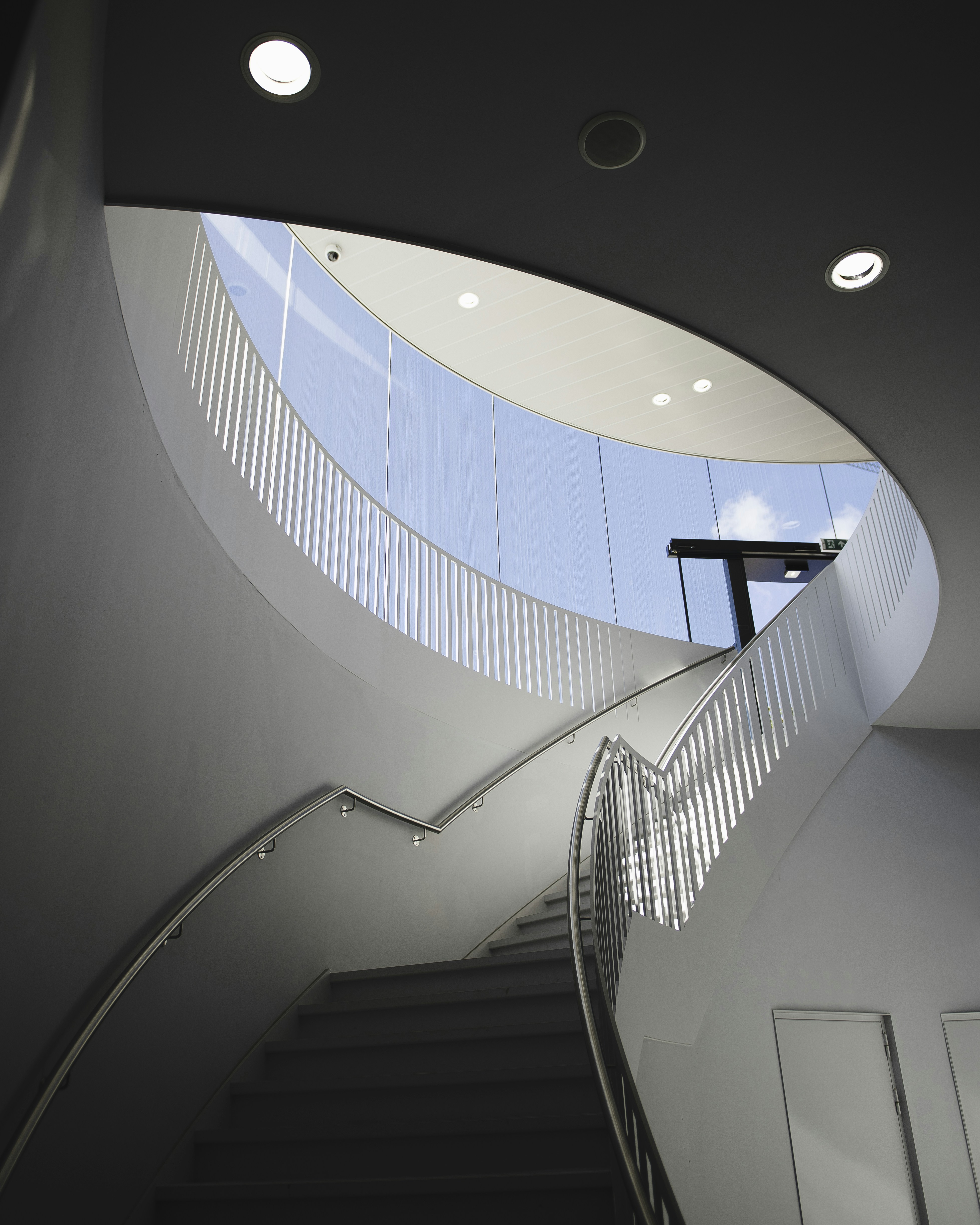 Spiral Ascent: A Modern Staircase Framed by Circular Balcony Windows