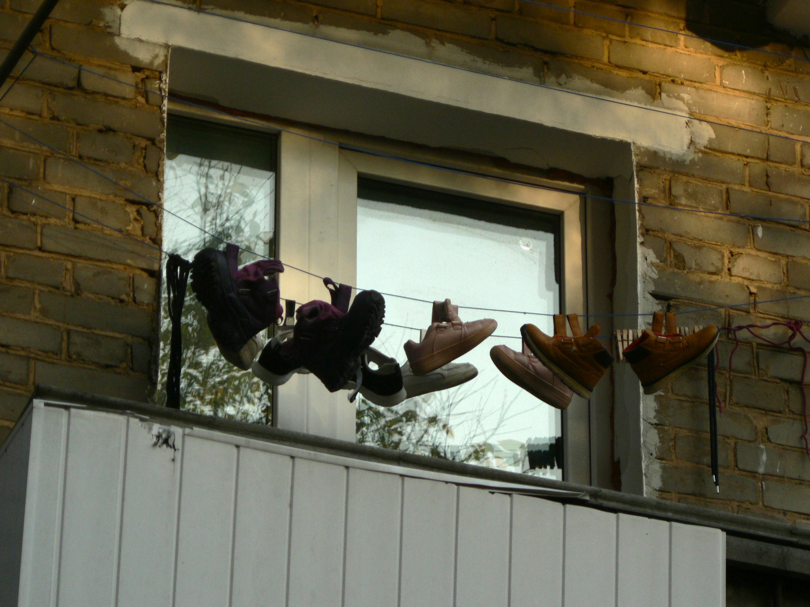 Shoes in Flight above a Sunlit Balcony