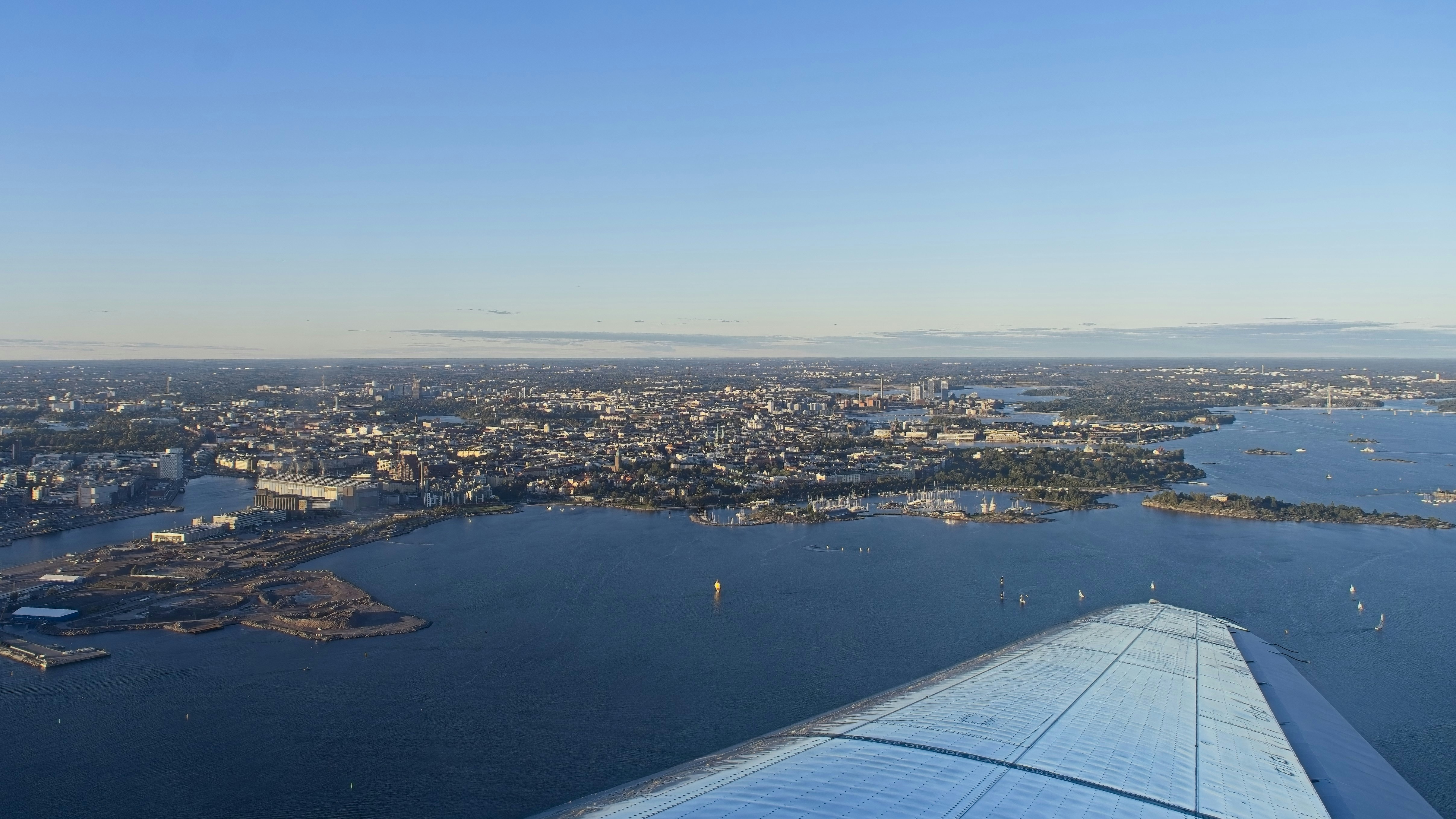Coastline and cityscape unfurl from the wingtip: ocean, shore, and urban grid