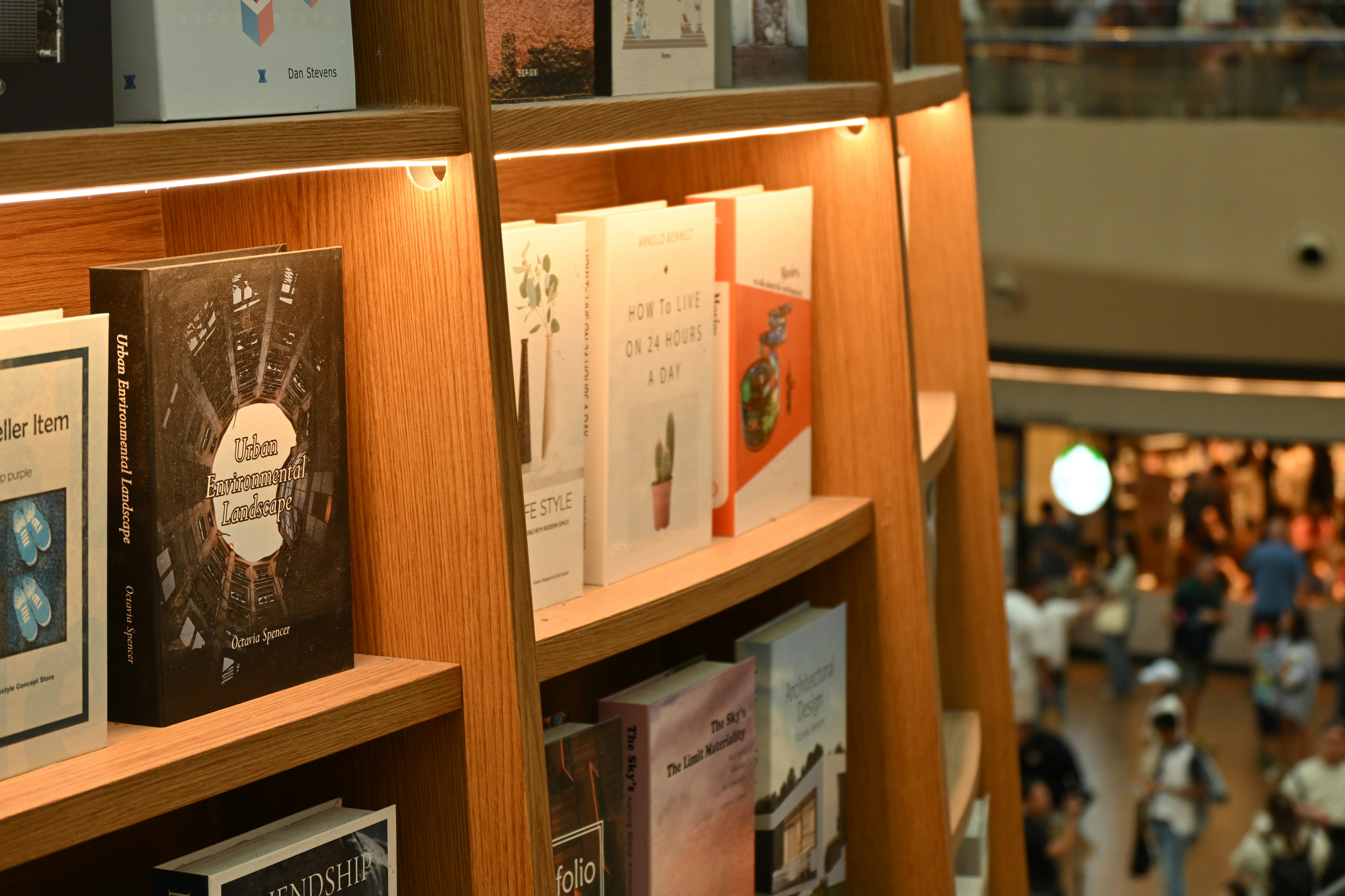 Warmly lit library shelves filled with books against a blurred bustling background.