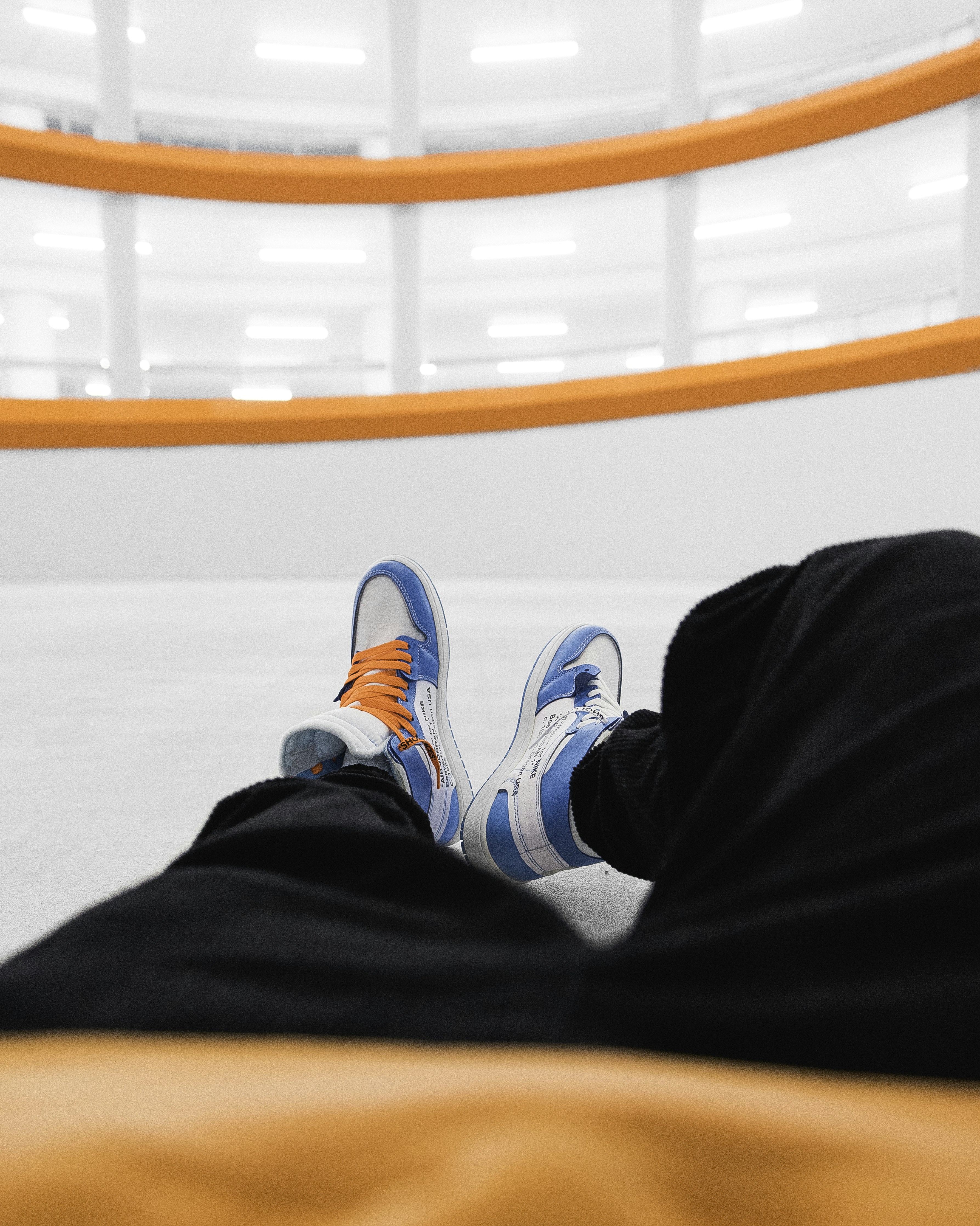 Shoes and legs in a bright blue skate-sneaker scene from a low-angle lounge