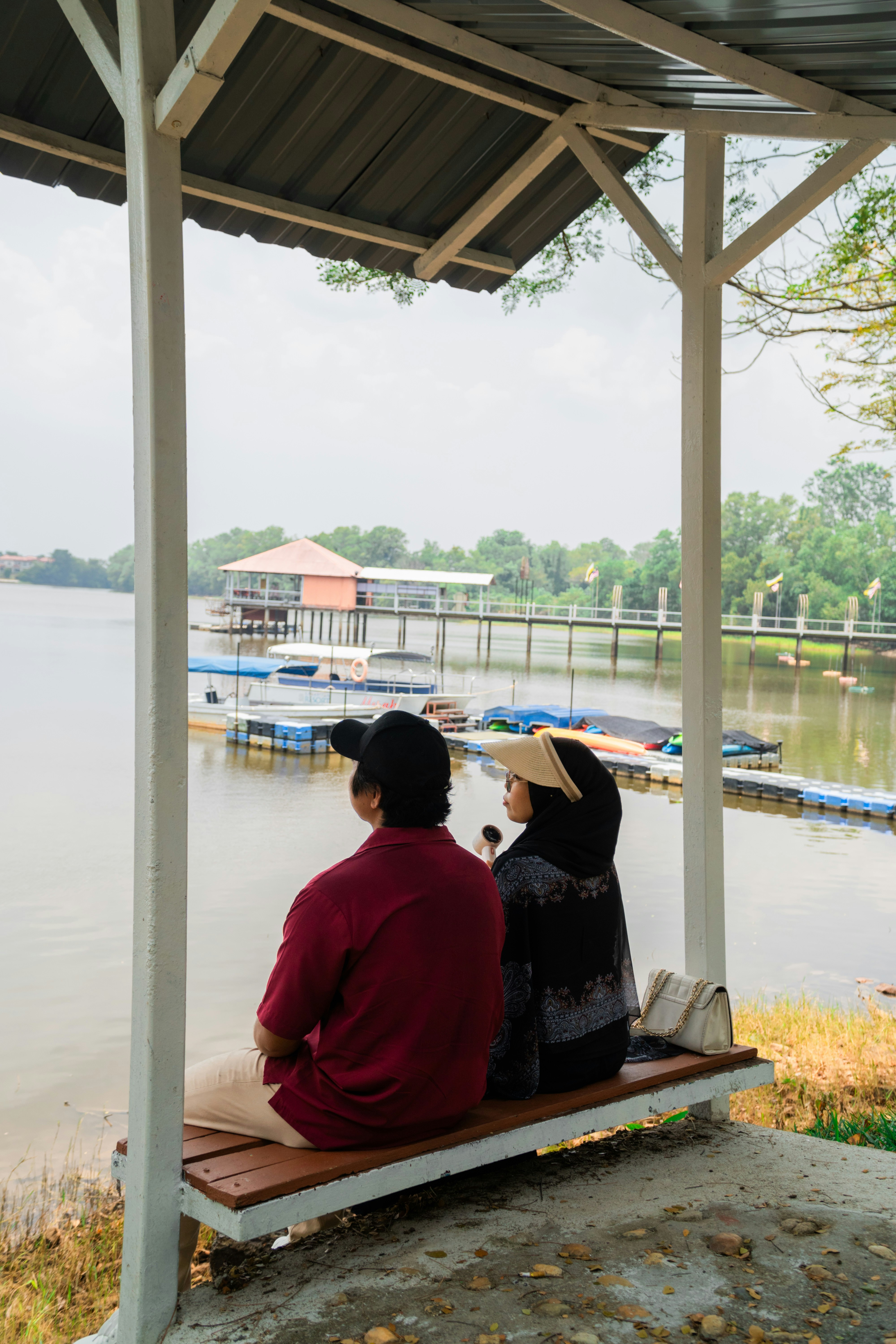 Quiet Riverside Bench: A Couple Watching Boats by the Shed