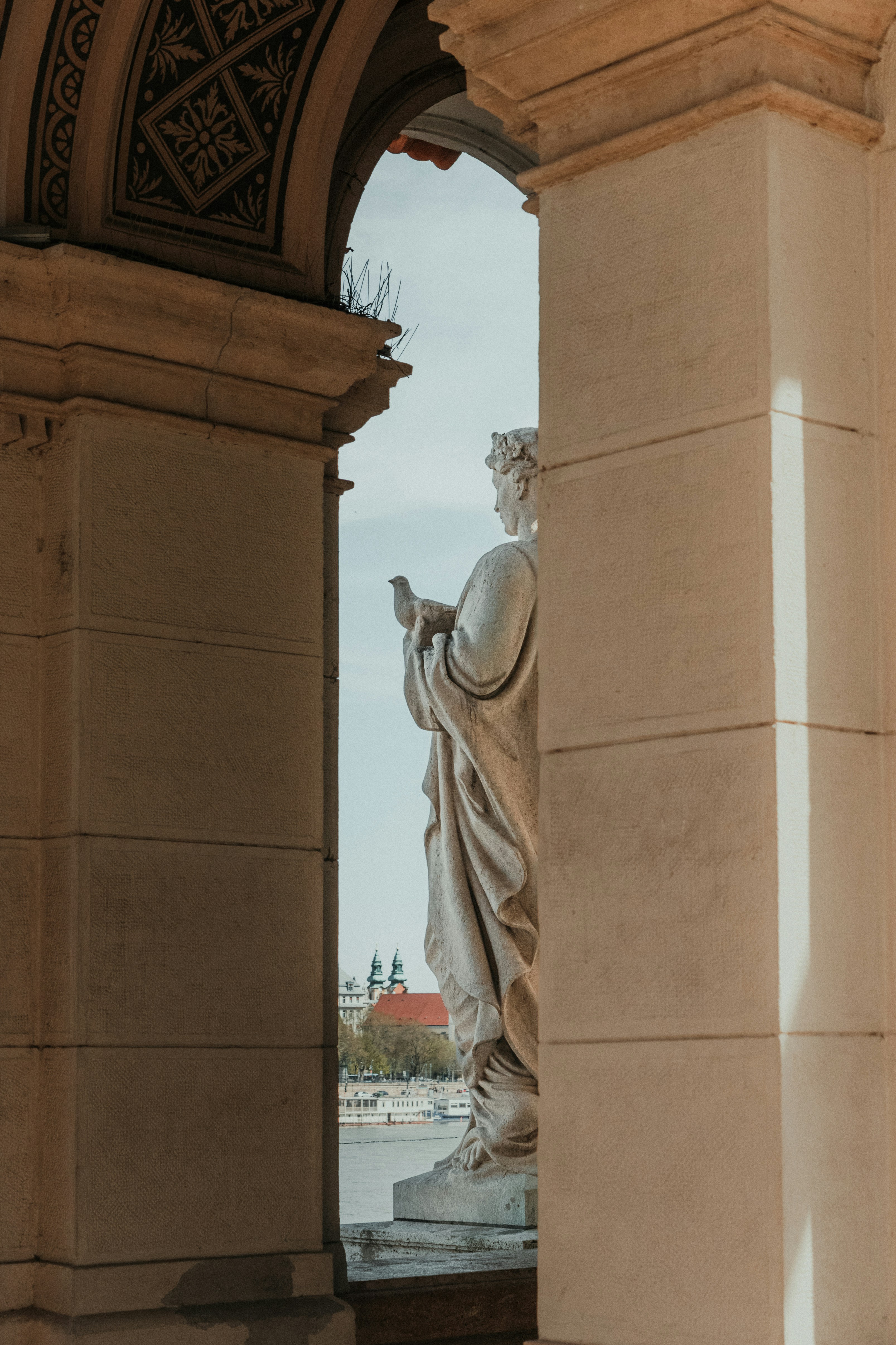 Statue Framed by Classical Arch: A Quiet Gaze by the River