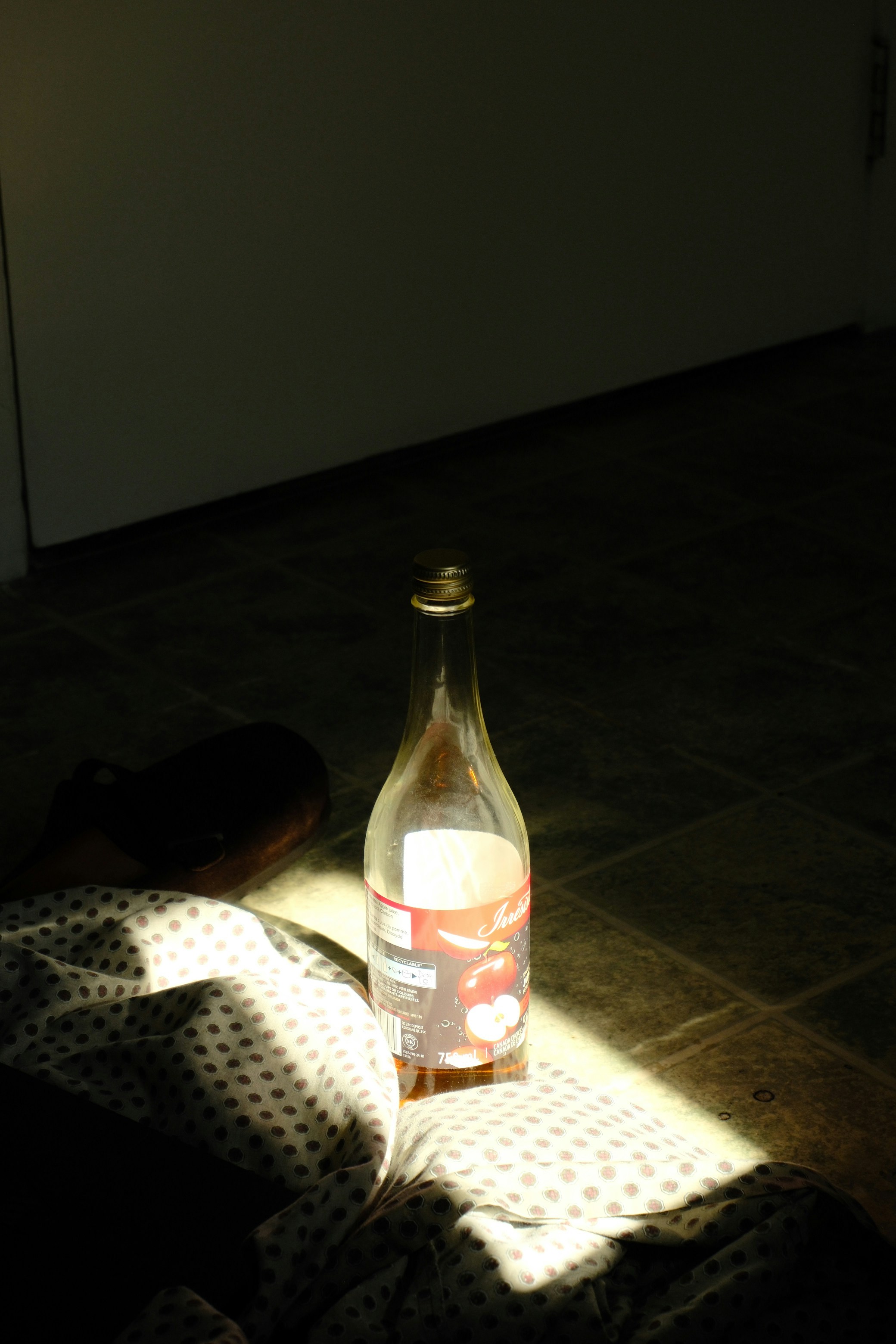 Dimly Lit Still Life: A Bottle Illuminated on a Polka-Dot Cloth