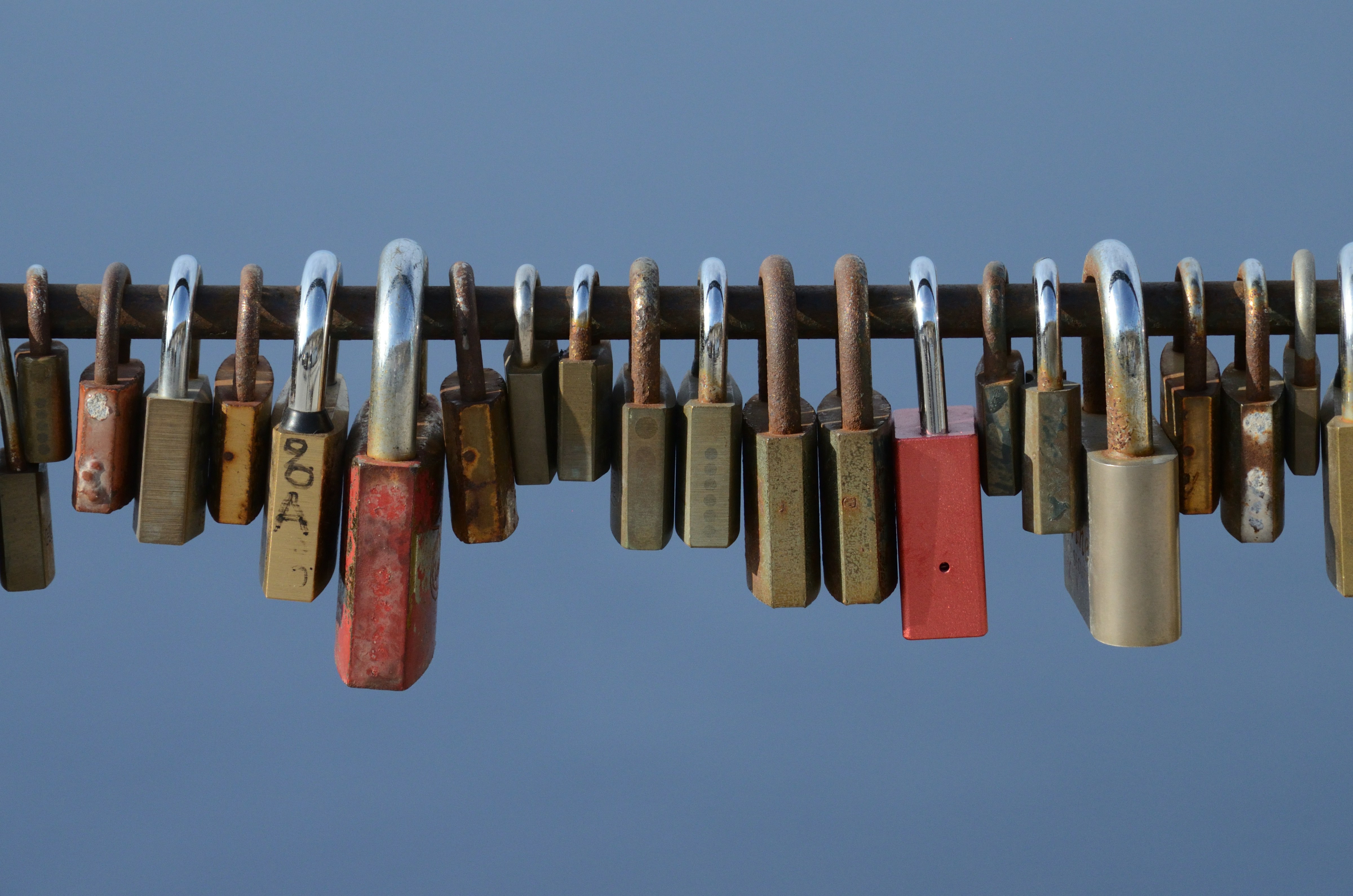 Padlocks in a clear blue sky: a row of colorful locks on a wire