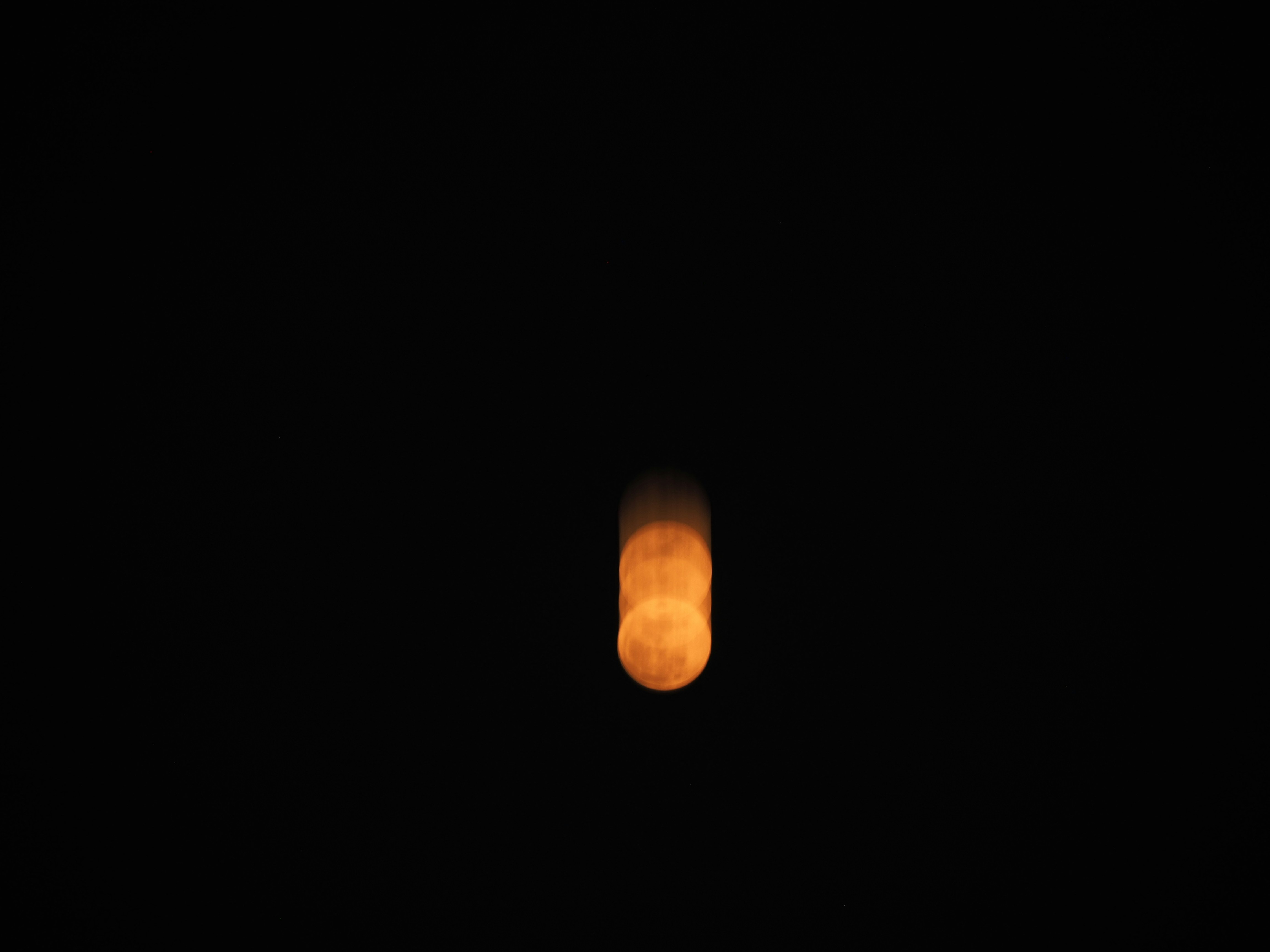 A motion blurred orange moon against a dark night sky