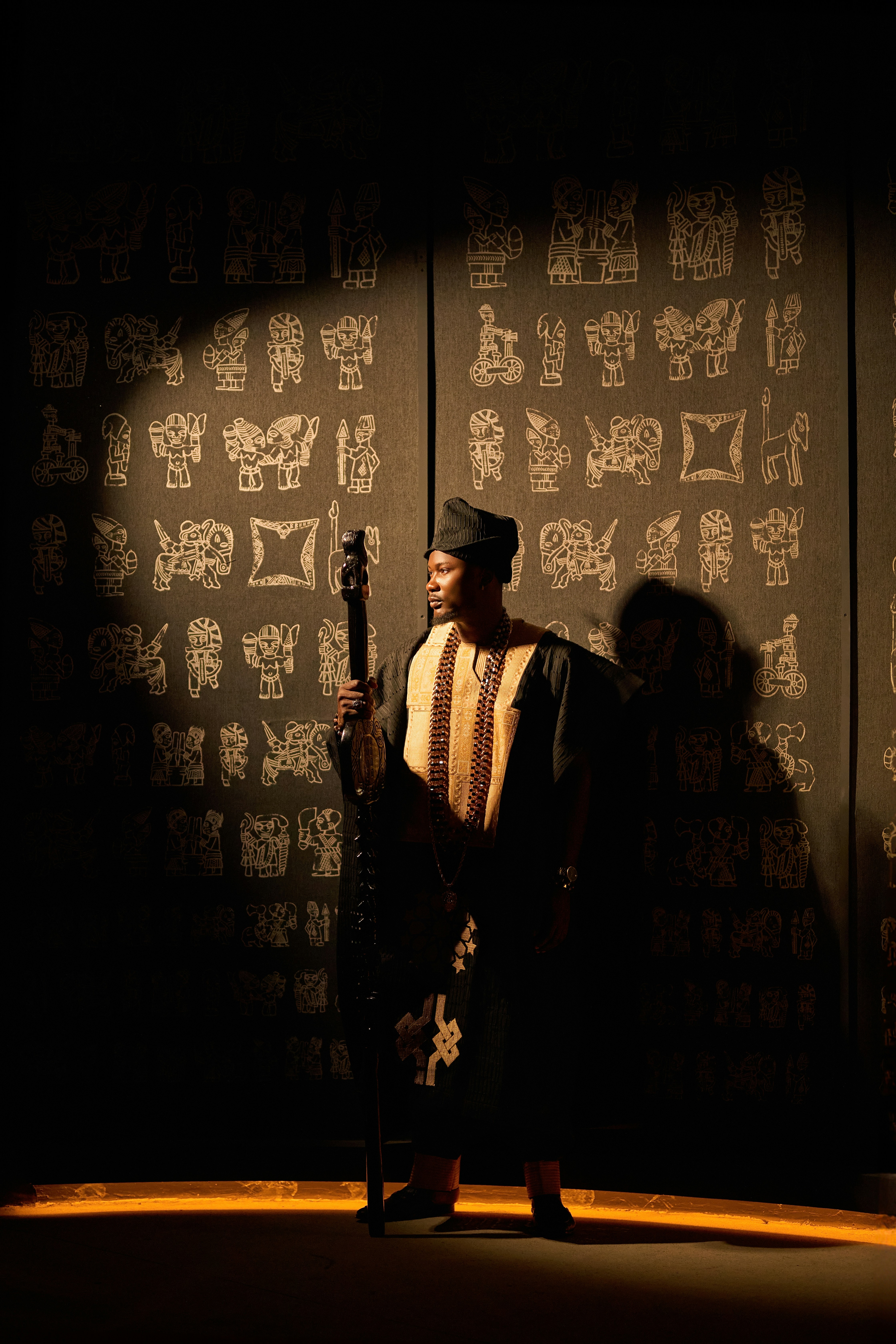 Shadowed Custodian of Sound: A Singer's Quiet Moment with a Griot's Staff