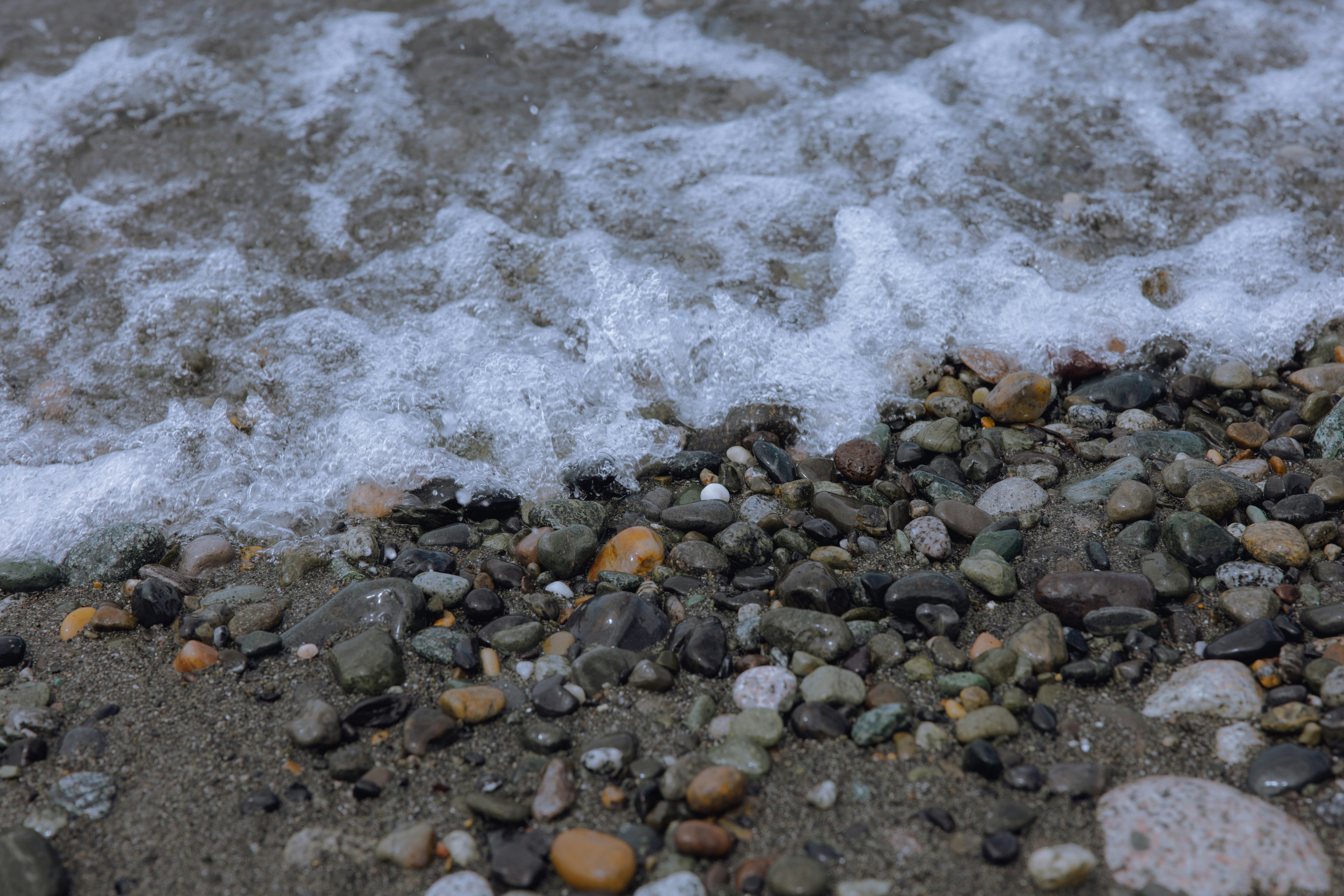 Pebble shoreline brushing against frothy tide