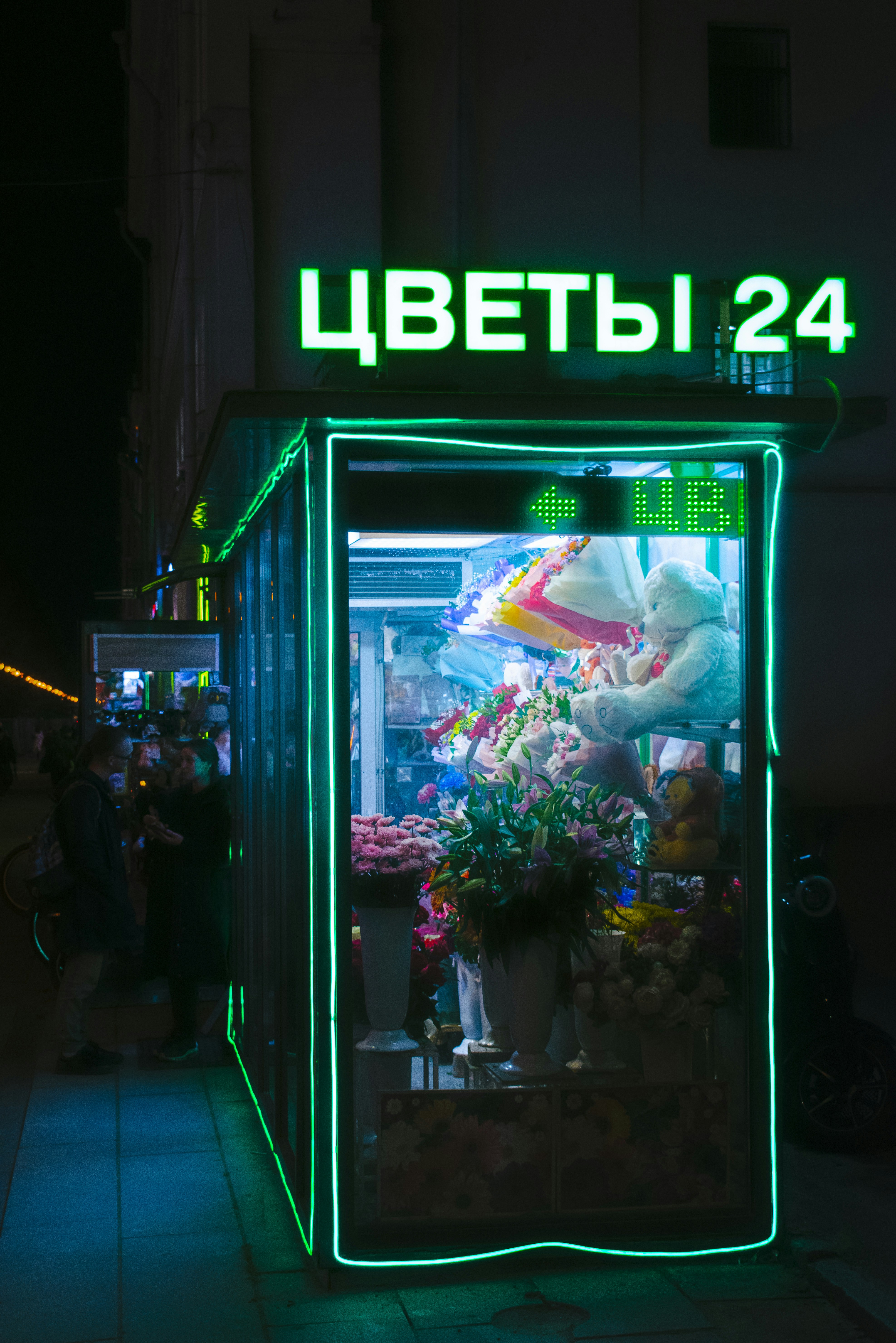 Neon Flower Kiosk Shimmering in Night Street