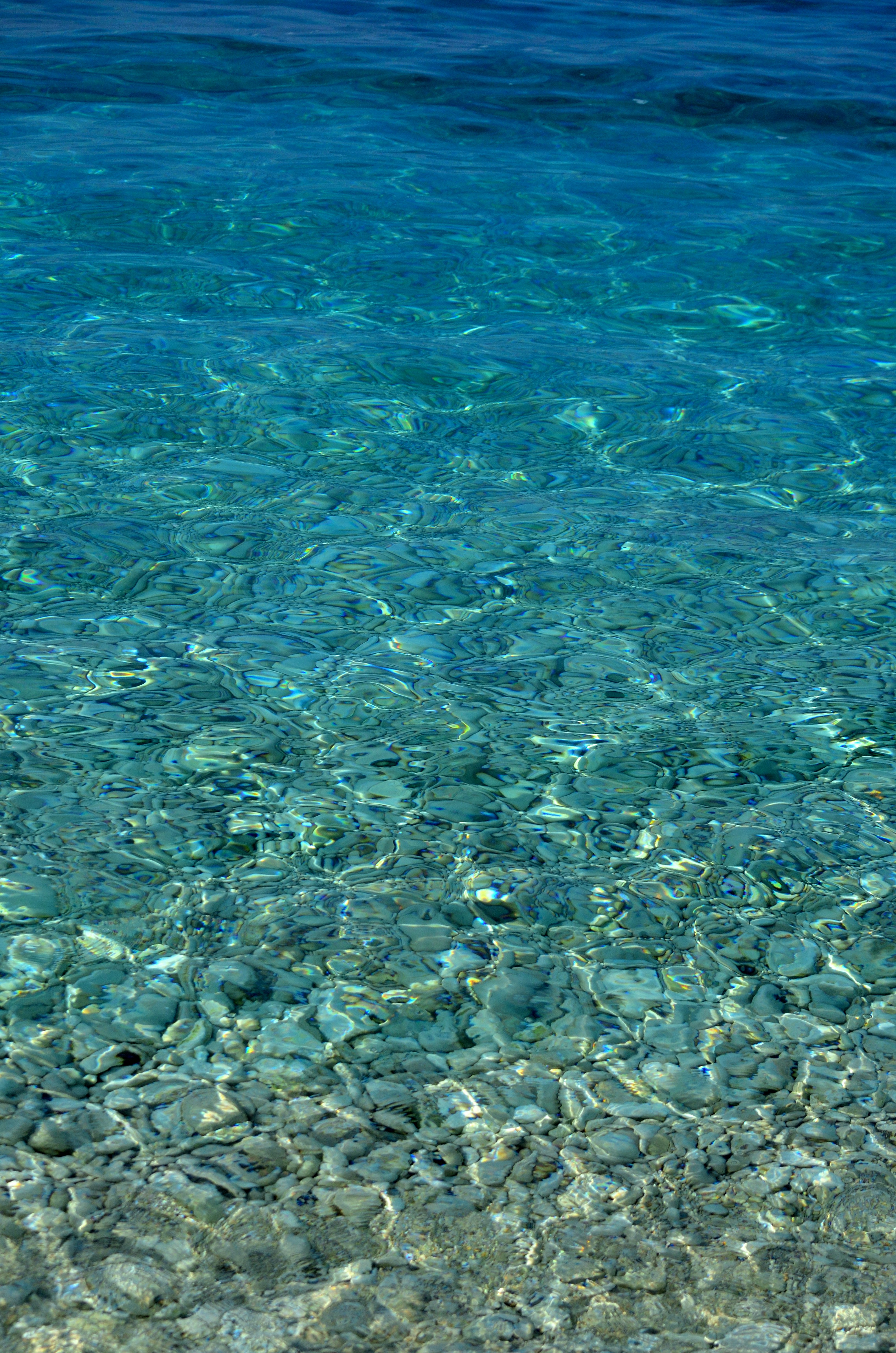 Crystal Veil: Sunlit Ripples over Pebble Shore