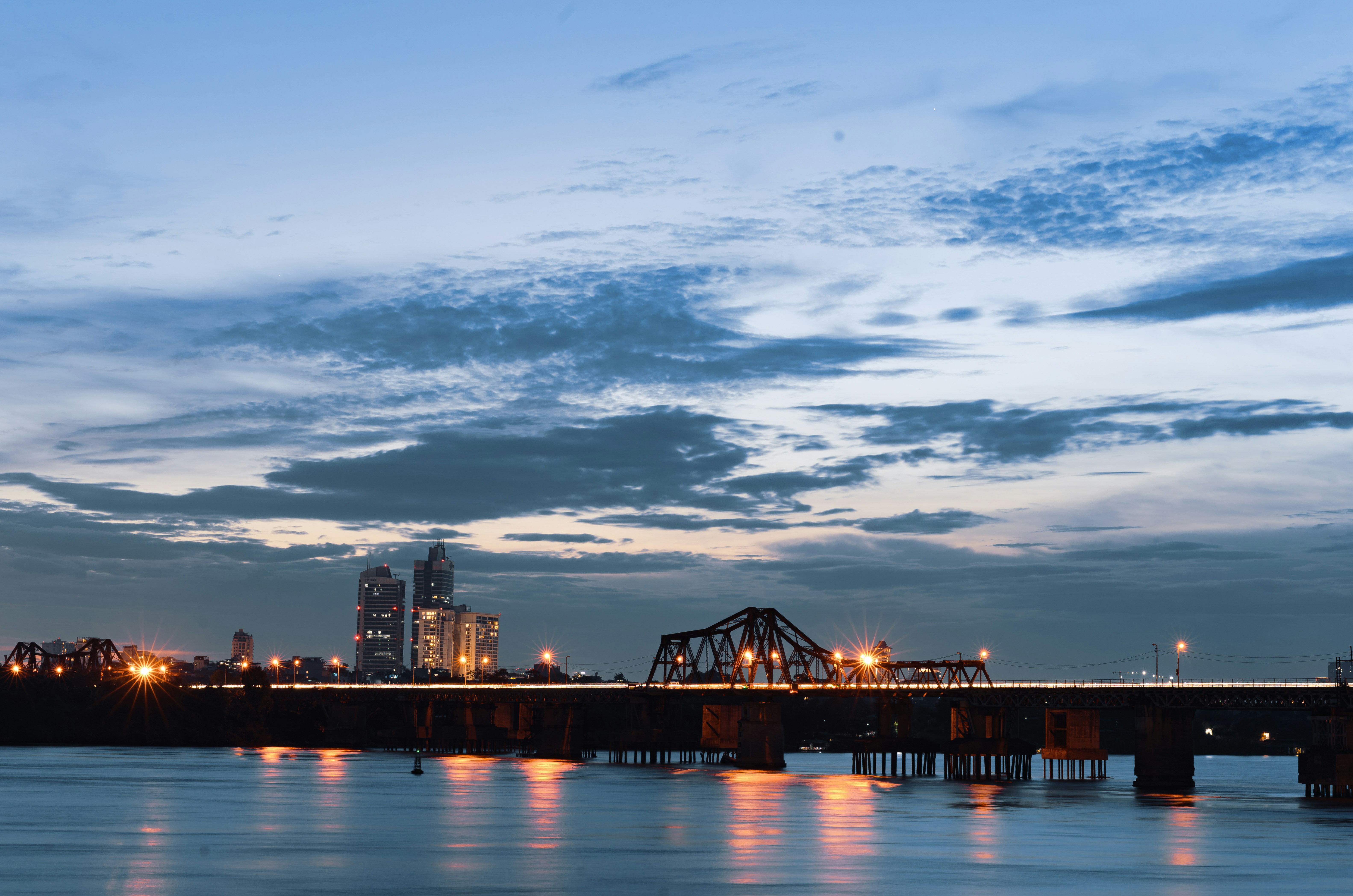 A steel truss bridge illuminated by streetlights over a river at night
