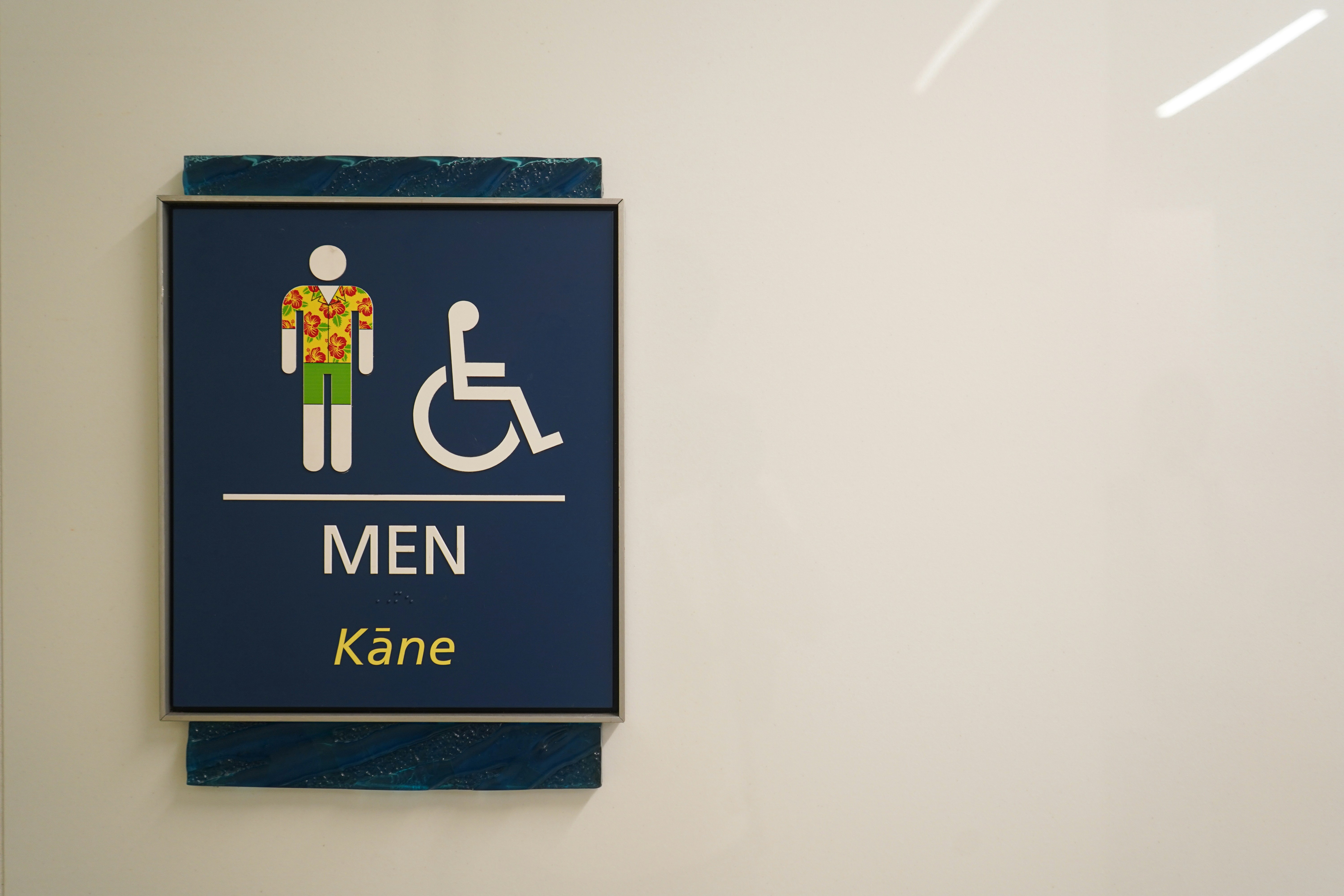 Colorful figure beside a wheelchair symbol on a dark blue bathroom sign