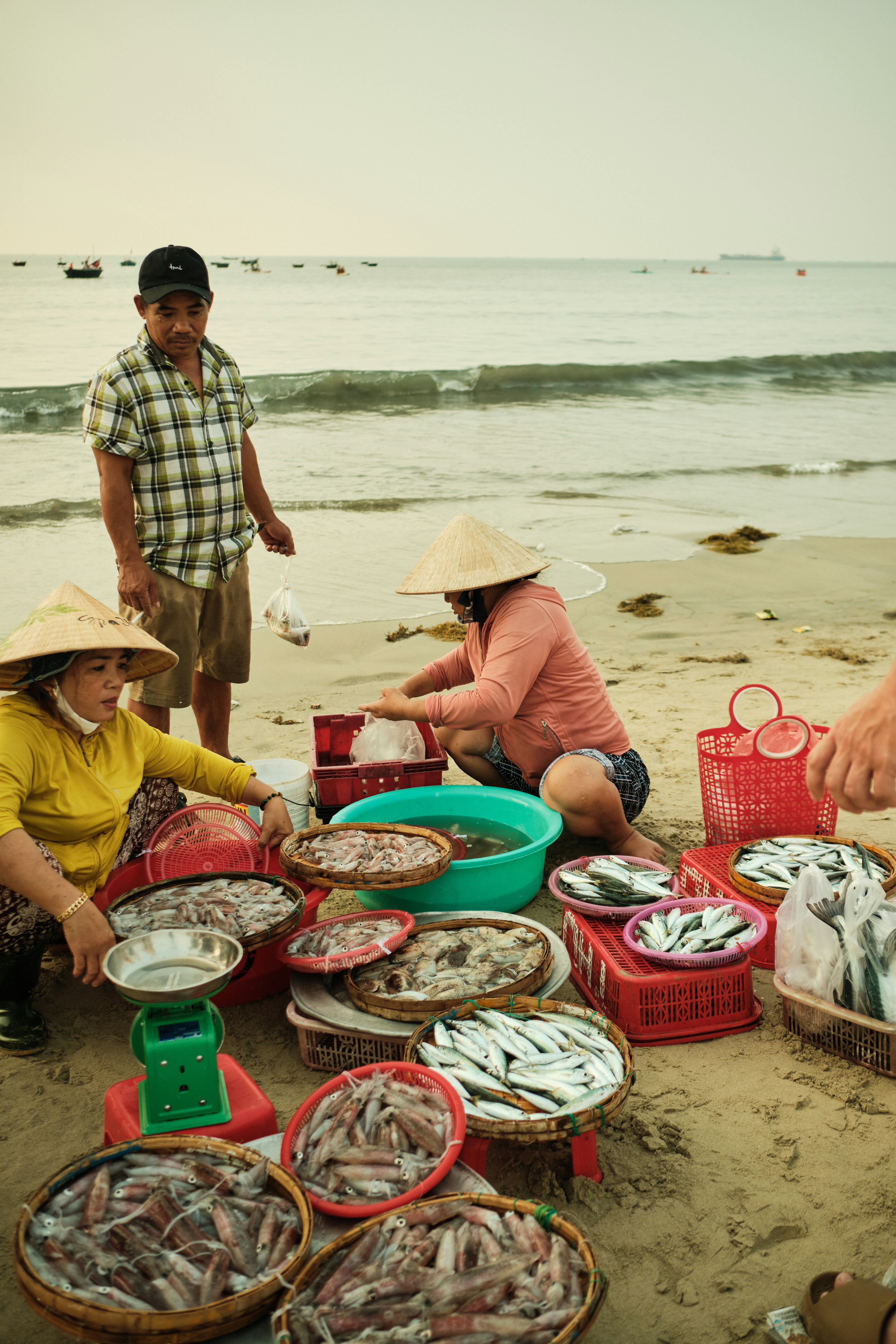 Market by the Shore: A Veteran Vendor and Fishermen at Dusk