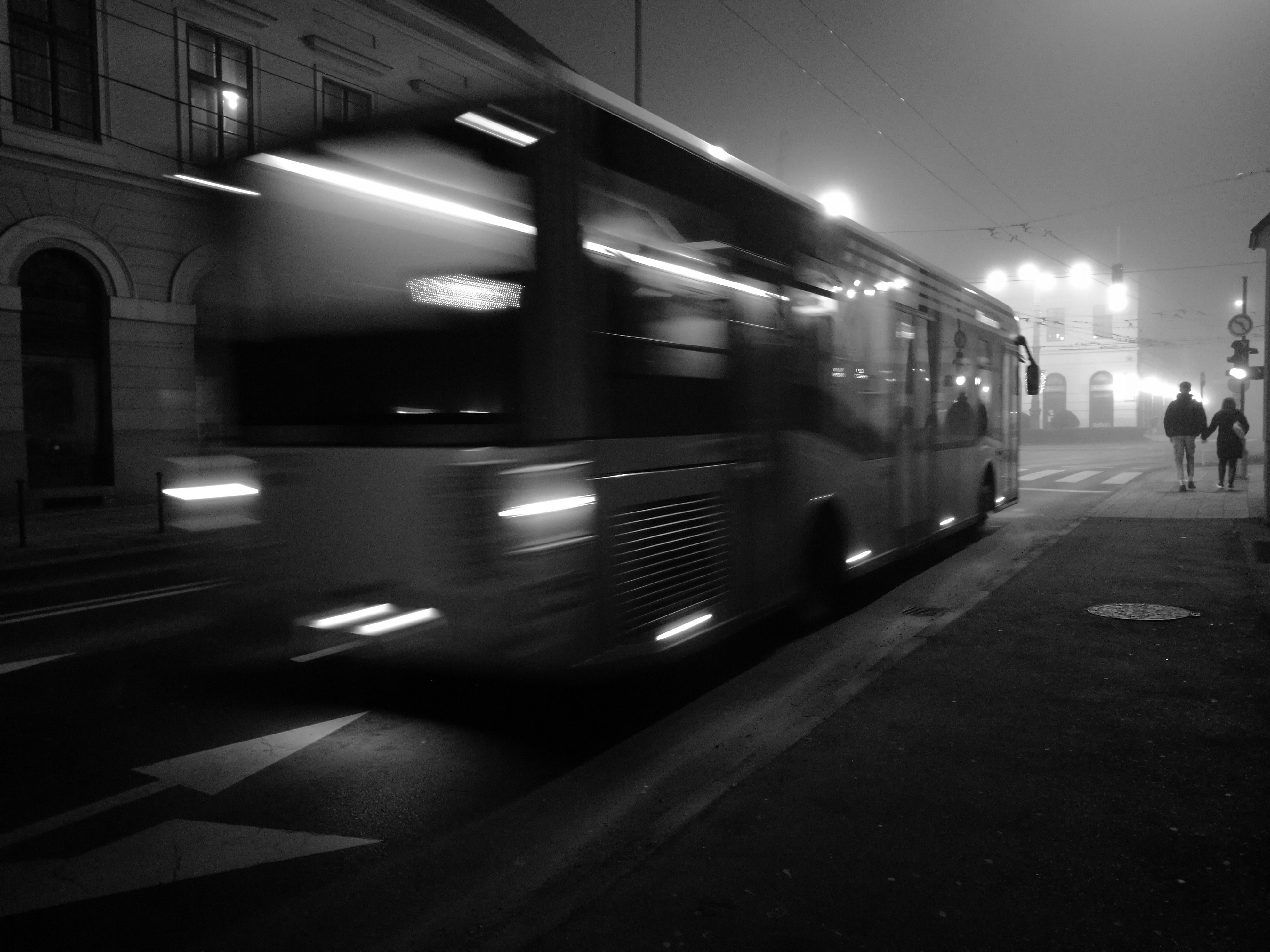 Night Bus in Motion: Blurred Neon and Two Pedestrians Ahead