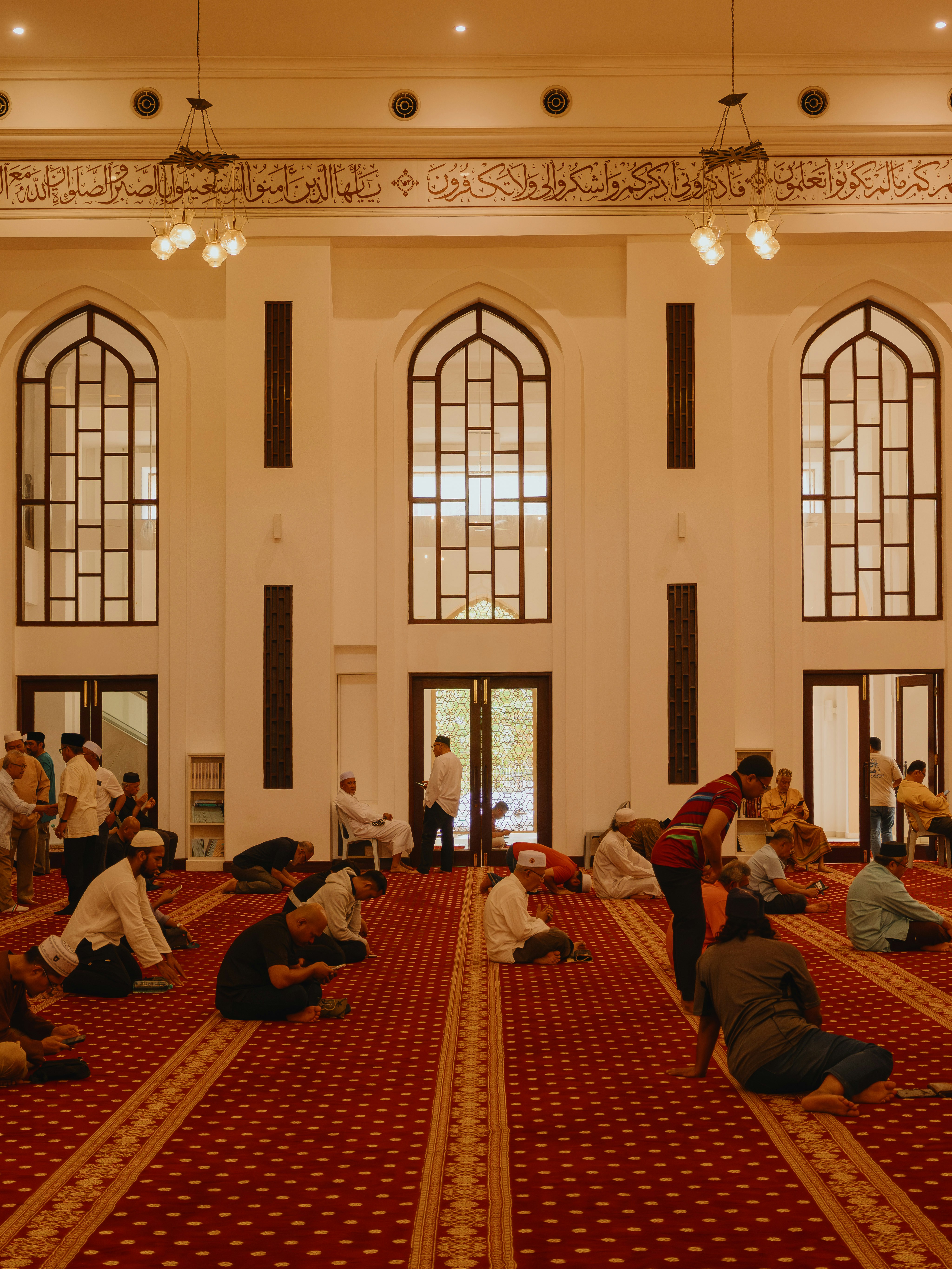 Quiet Prayer Floor: People Inside a Mosque Hall with Tall Arched Windows