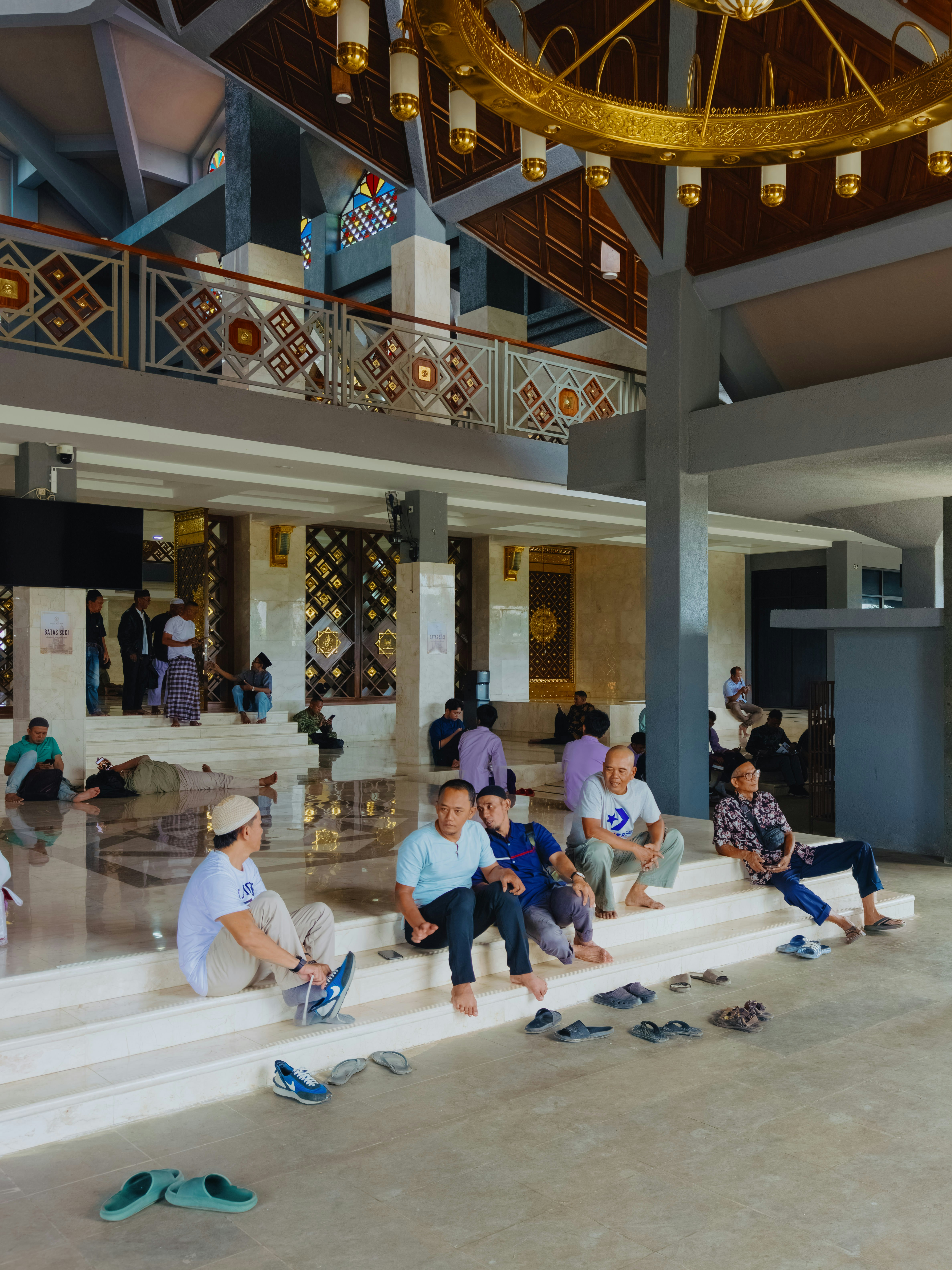 People resting on marble steps inside a grand, ornately decorated hall