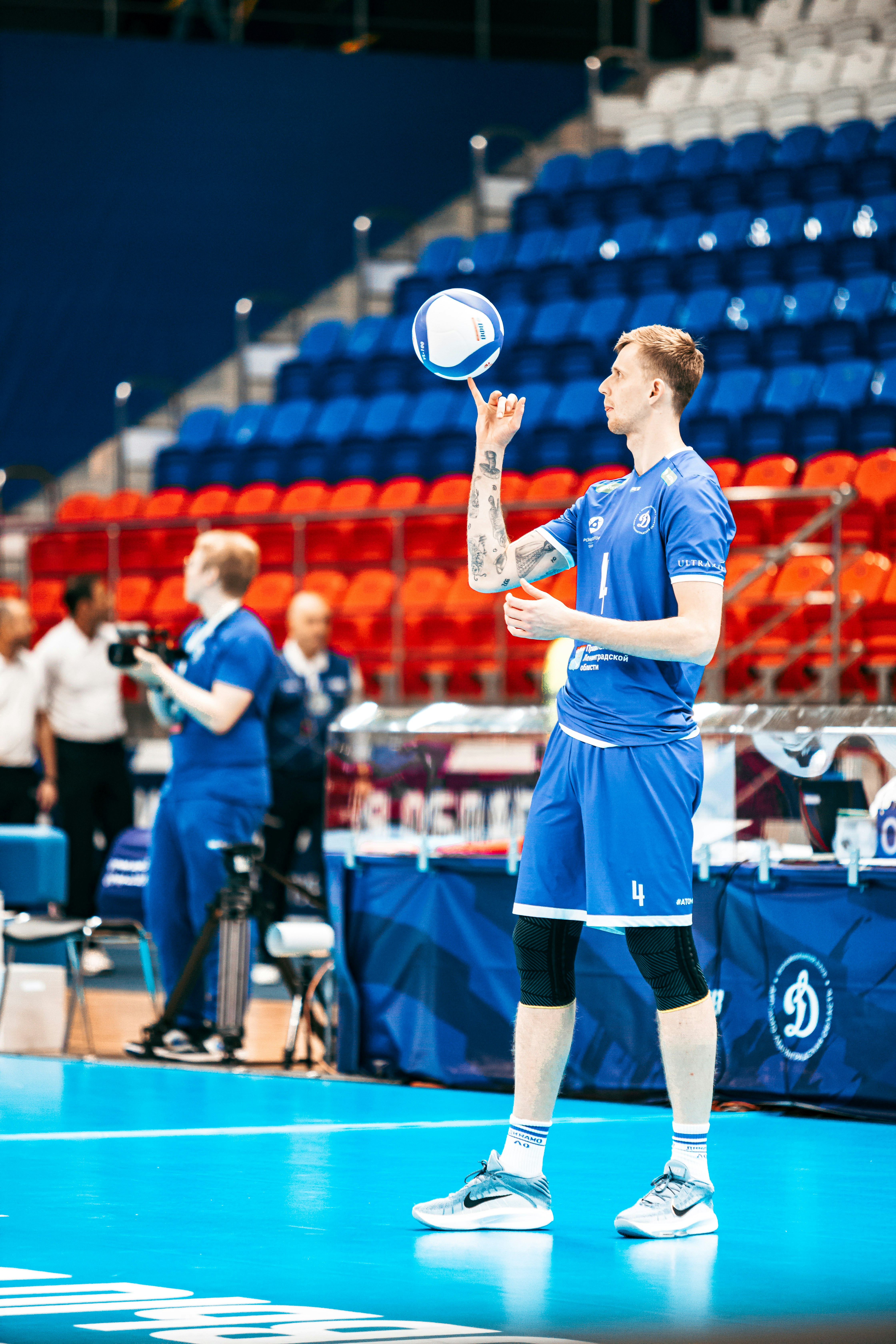 Volleyball Player in Blue Uniform Balancing a Ball Amidst a Colorful Arena