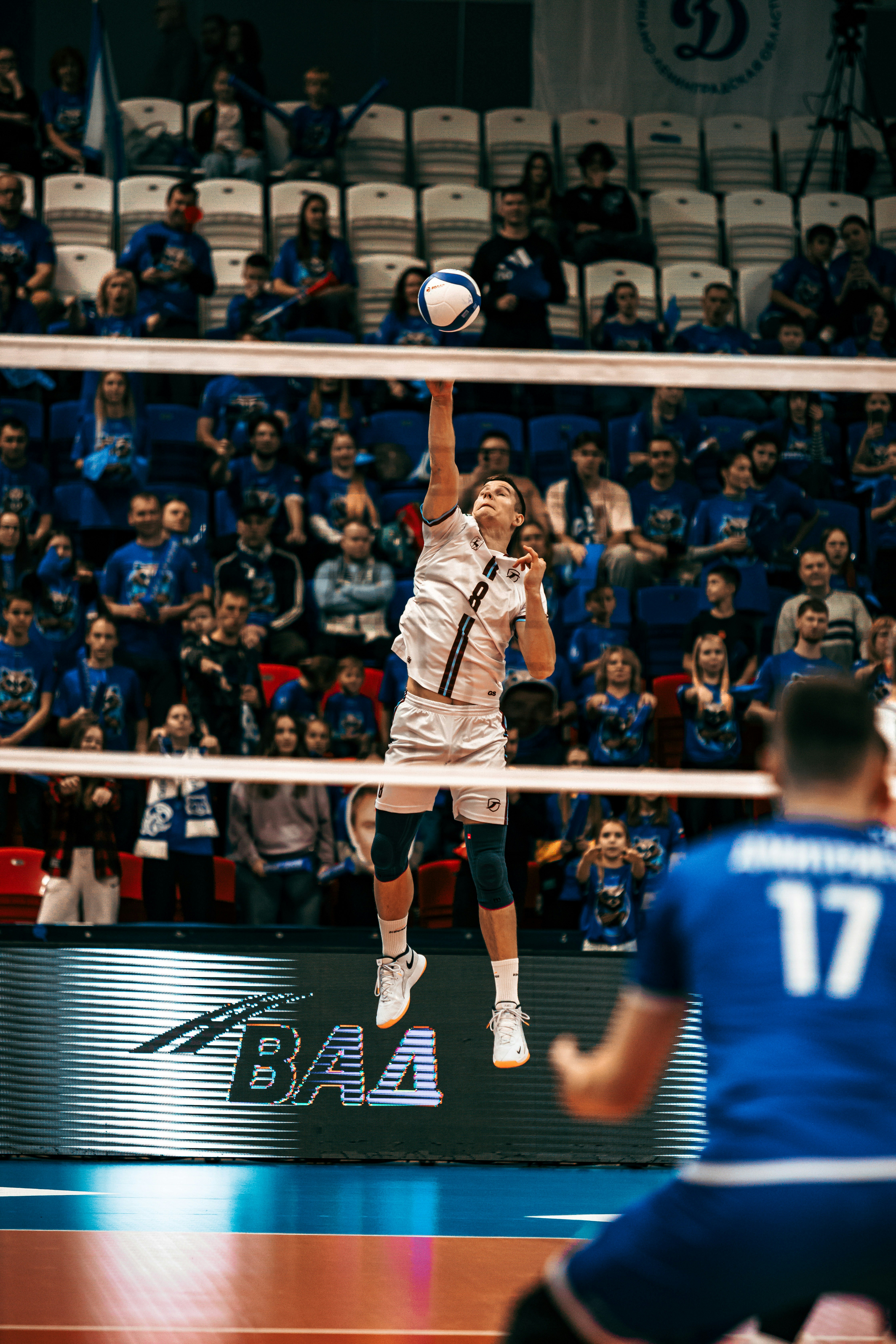 Leaping Volleyball Attack: A Player Elevates Against a Packed Arena