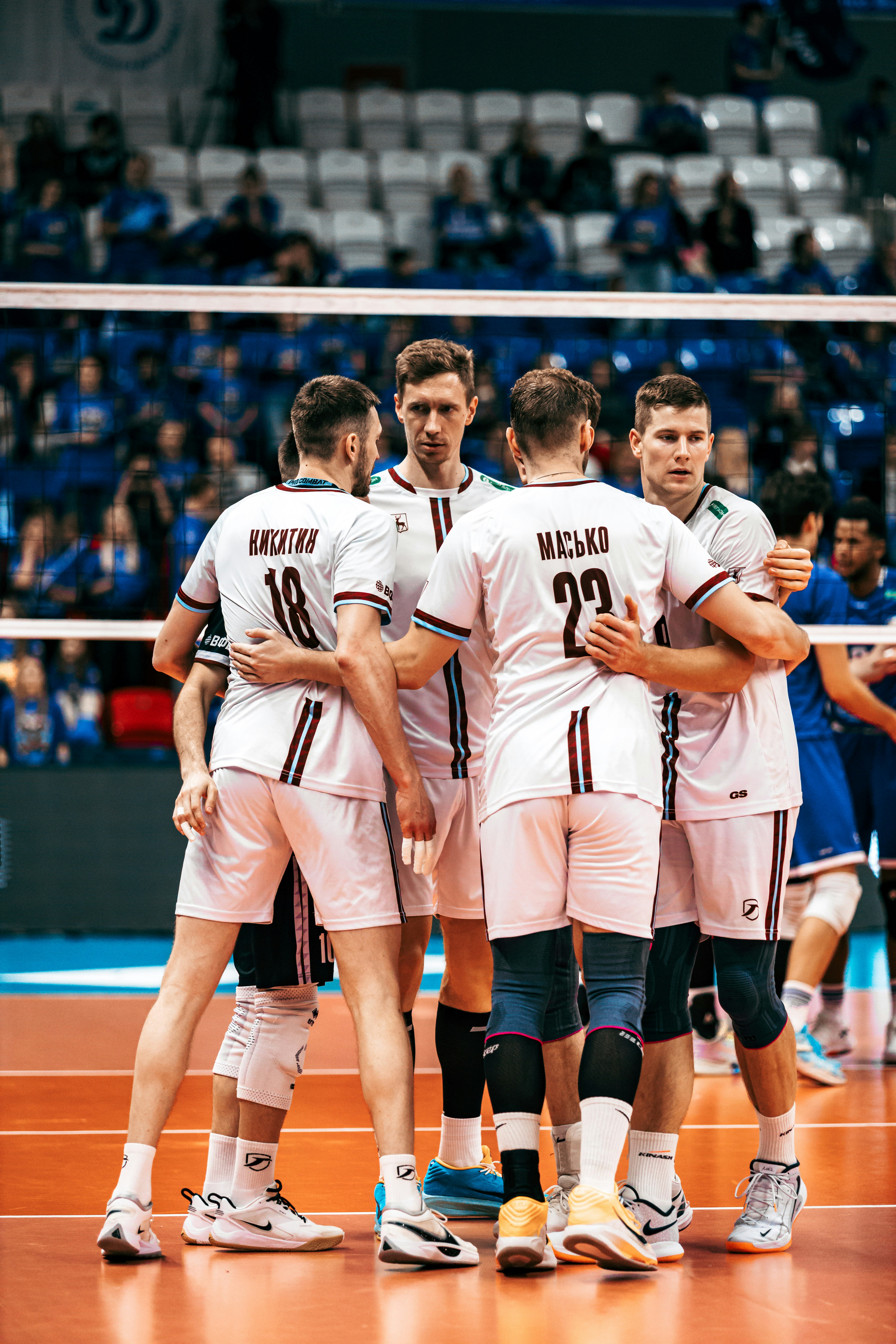 Team Huddle After Victory: White Jerseys Circle in the Volleyball Court