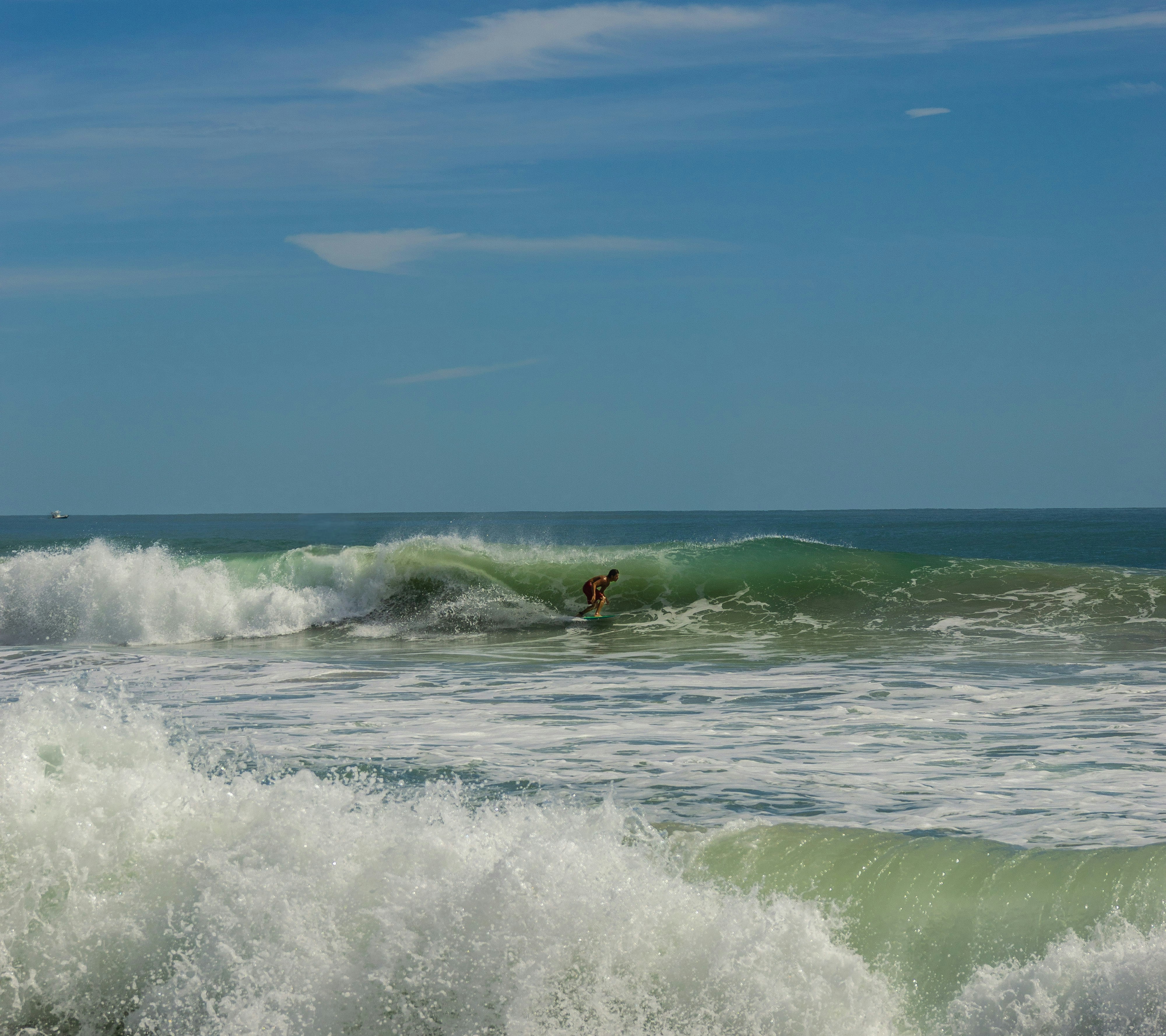 Solitary Surfer Riding a Green Wave Beyond a White-Crested Break