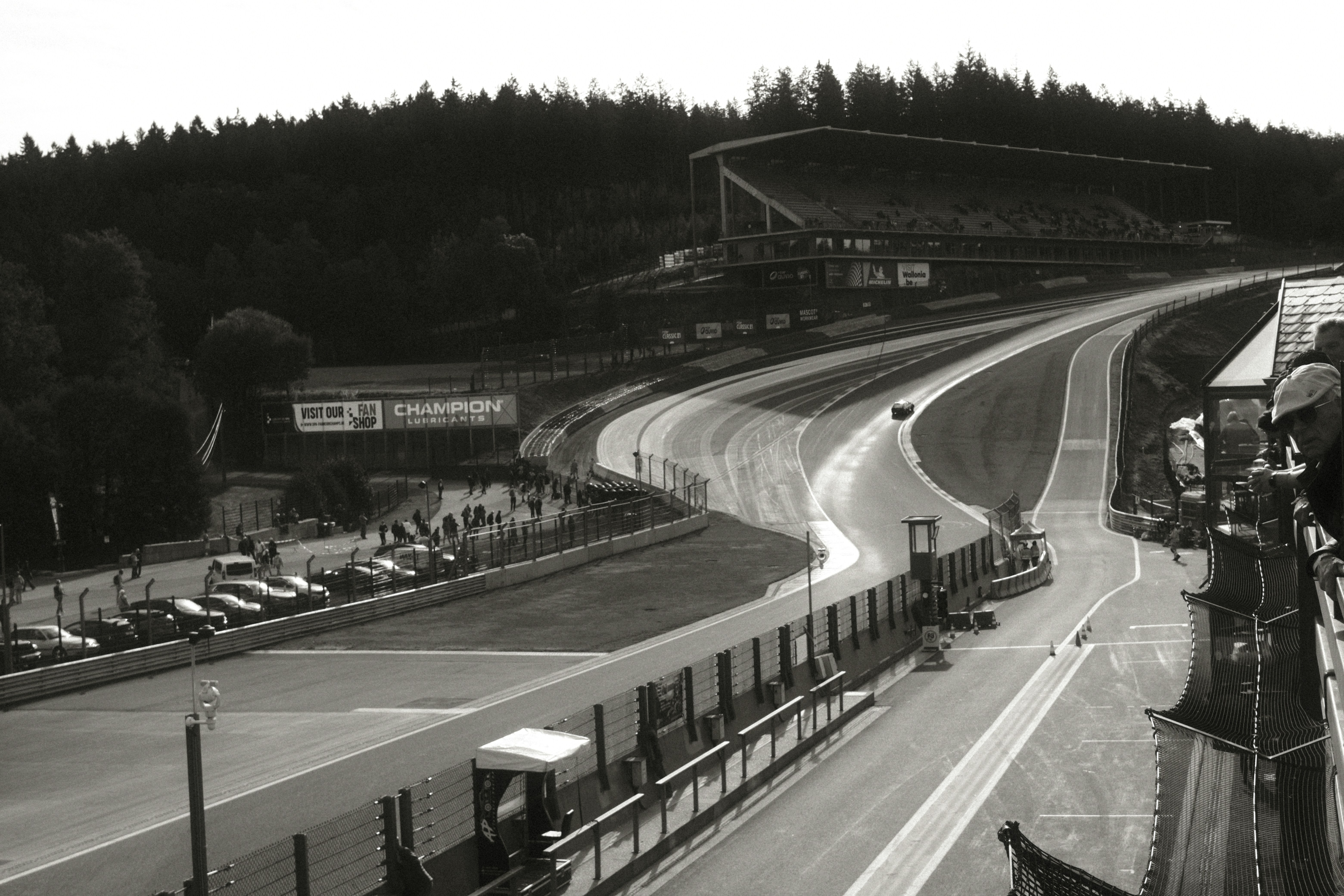 Circuit Curve: Cars Sprint Toward the Turn Under a Sweeping Grandstand