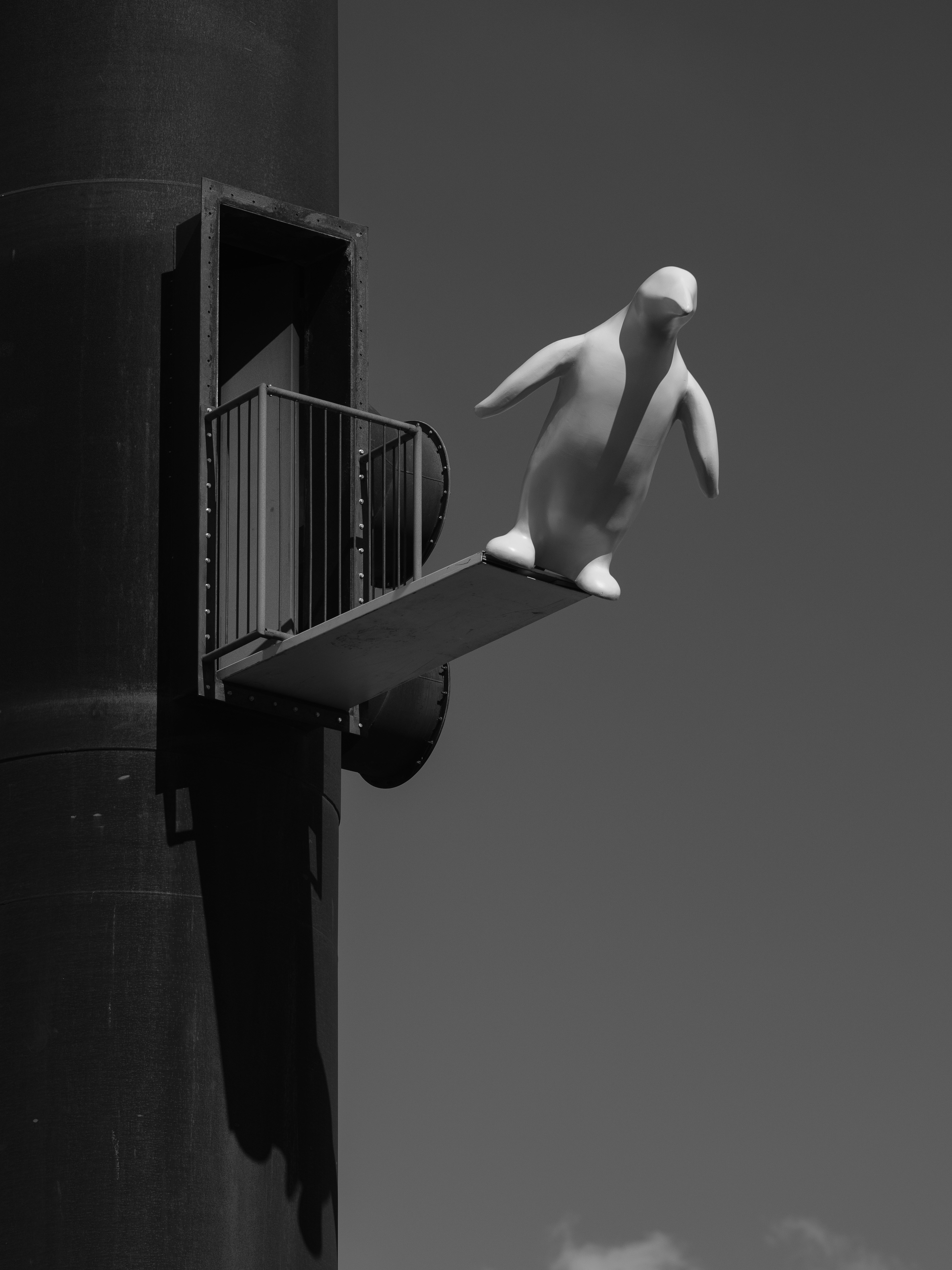 Abstract Descent: A Penguin Figurine Takes a Leap from Industrial Perch