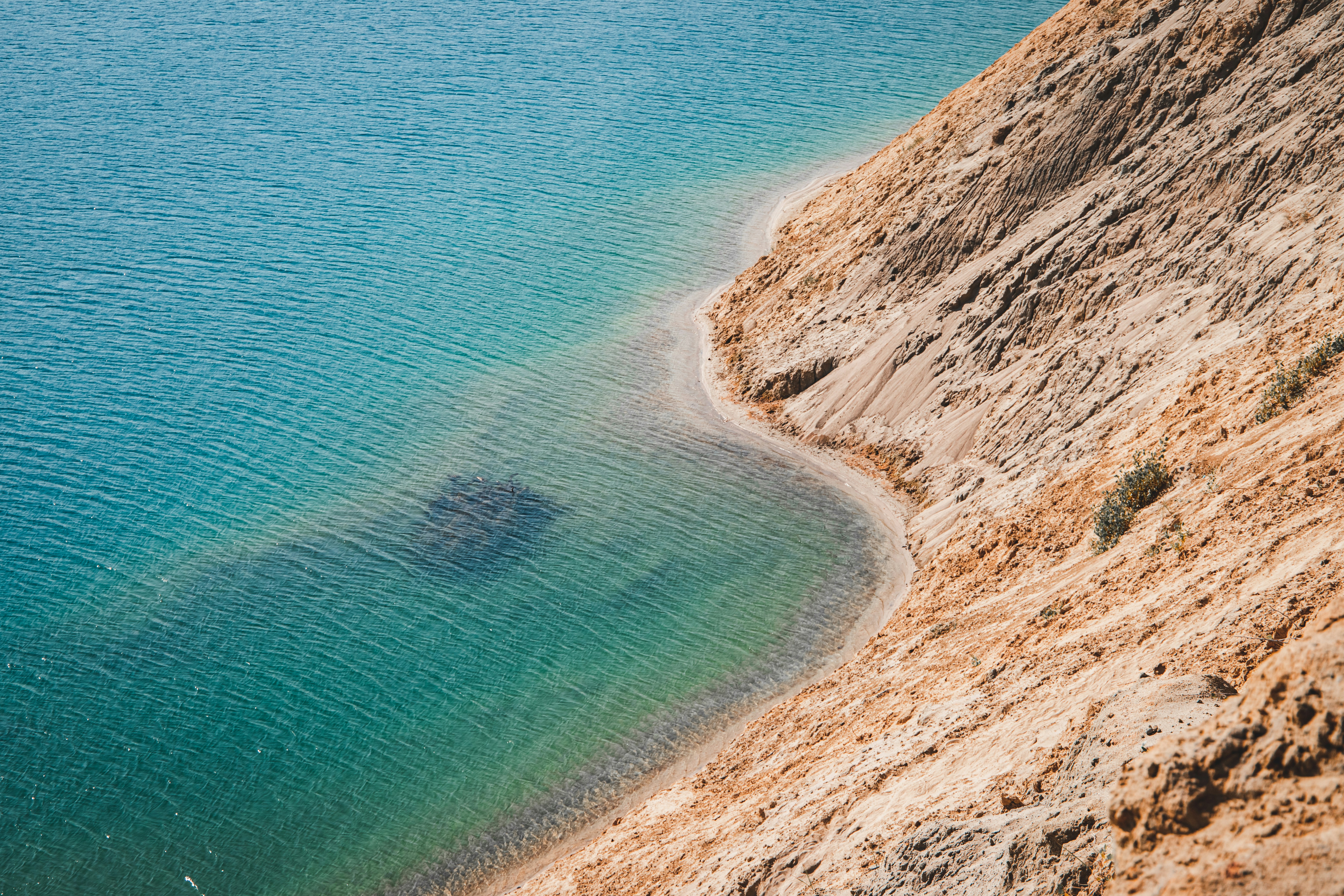 Aqua Cliffline: Turquoise Water Meeting Sunlit Sediments