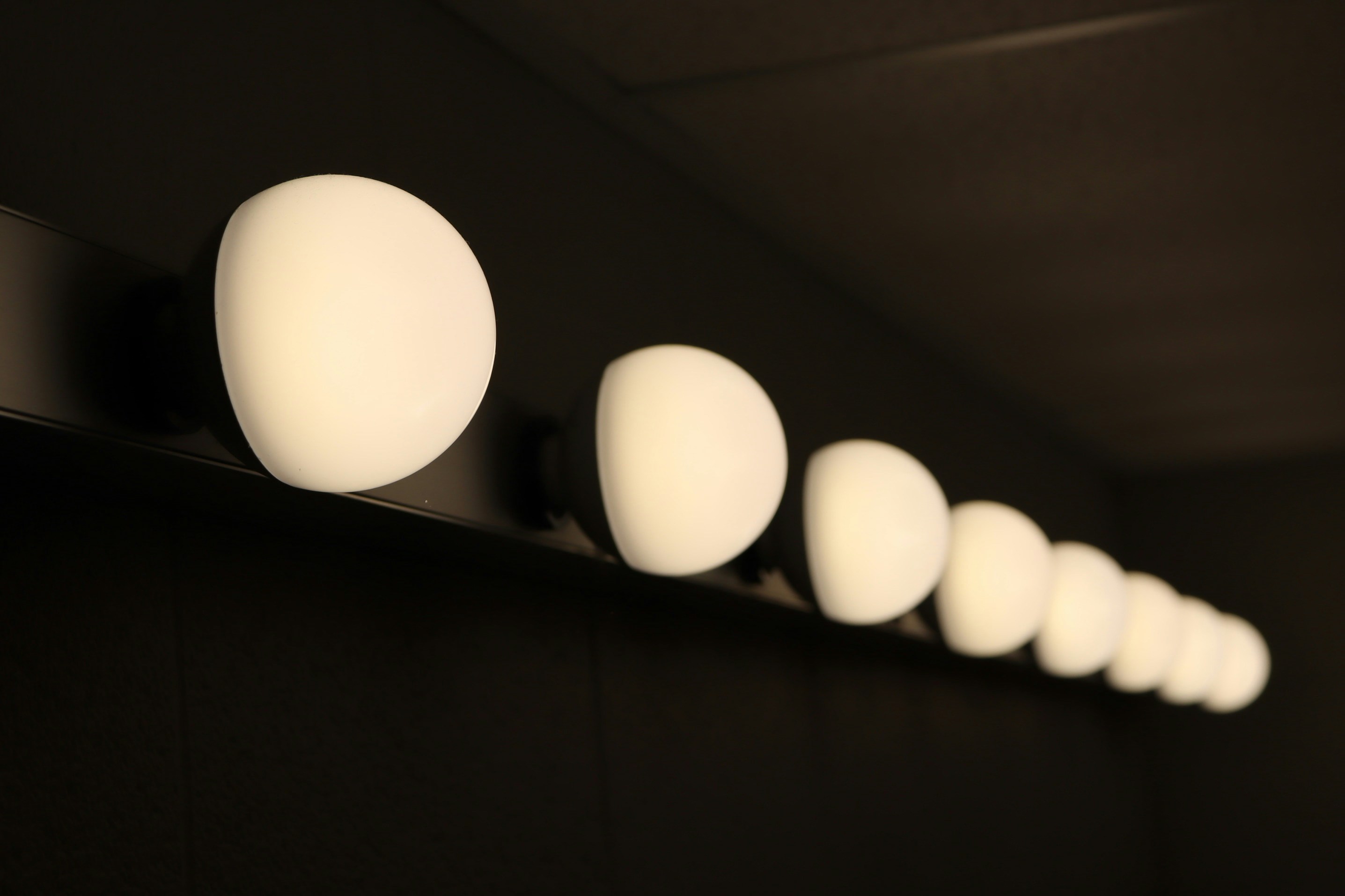 A sequence of softly glowing bulbs recedes into the darkness along a horizontal line.