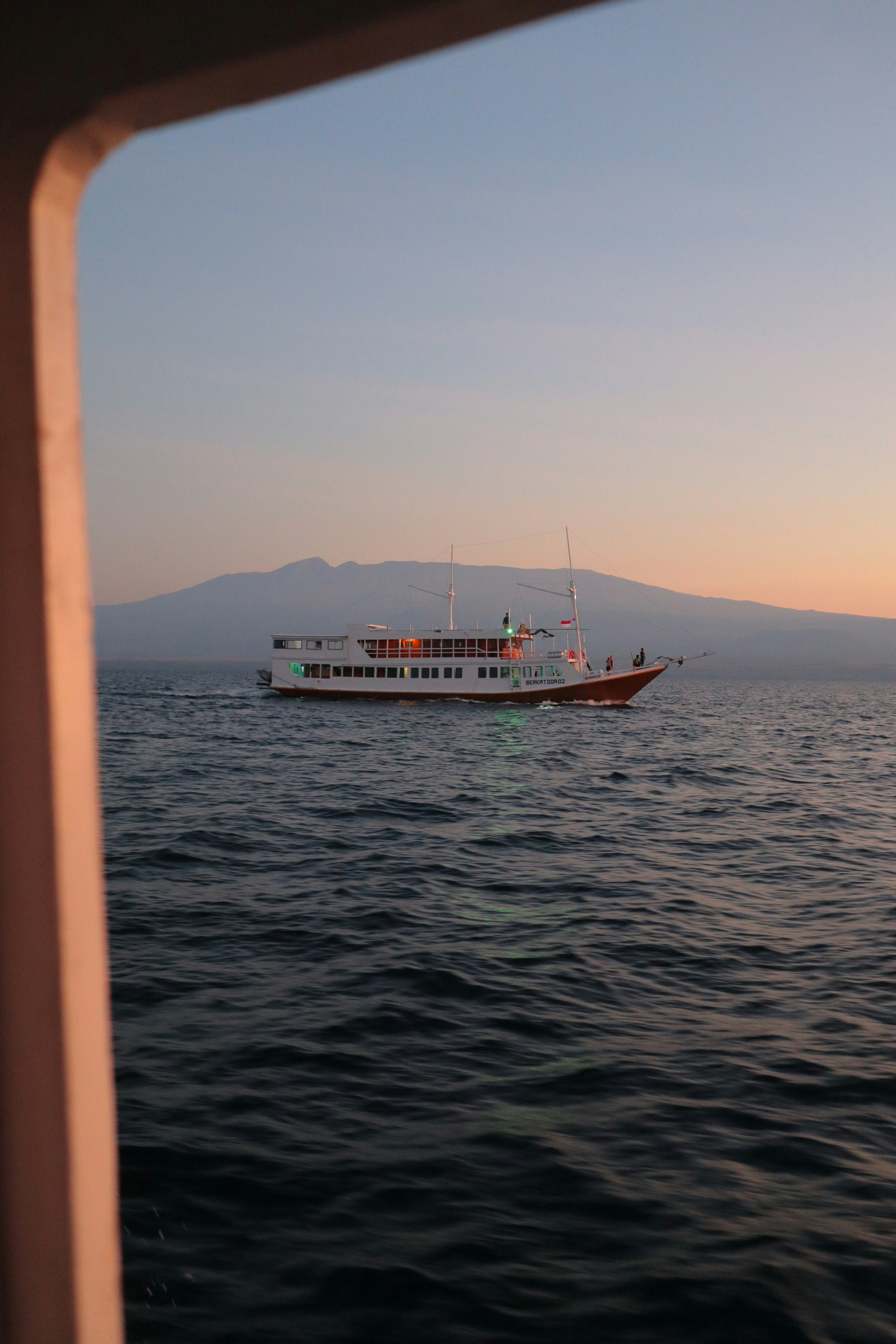 Sunset Sail: A Passenger Ferry Glides Past Mountains at Dusk