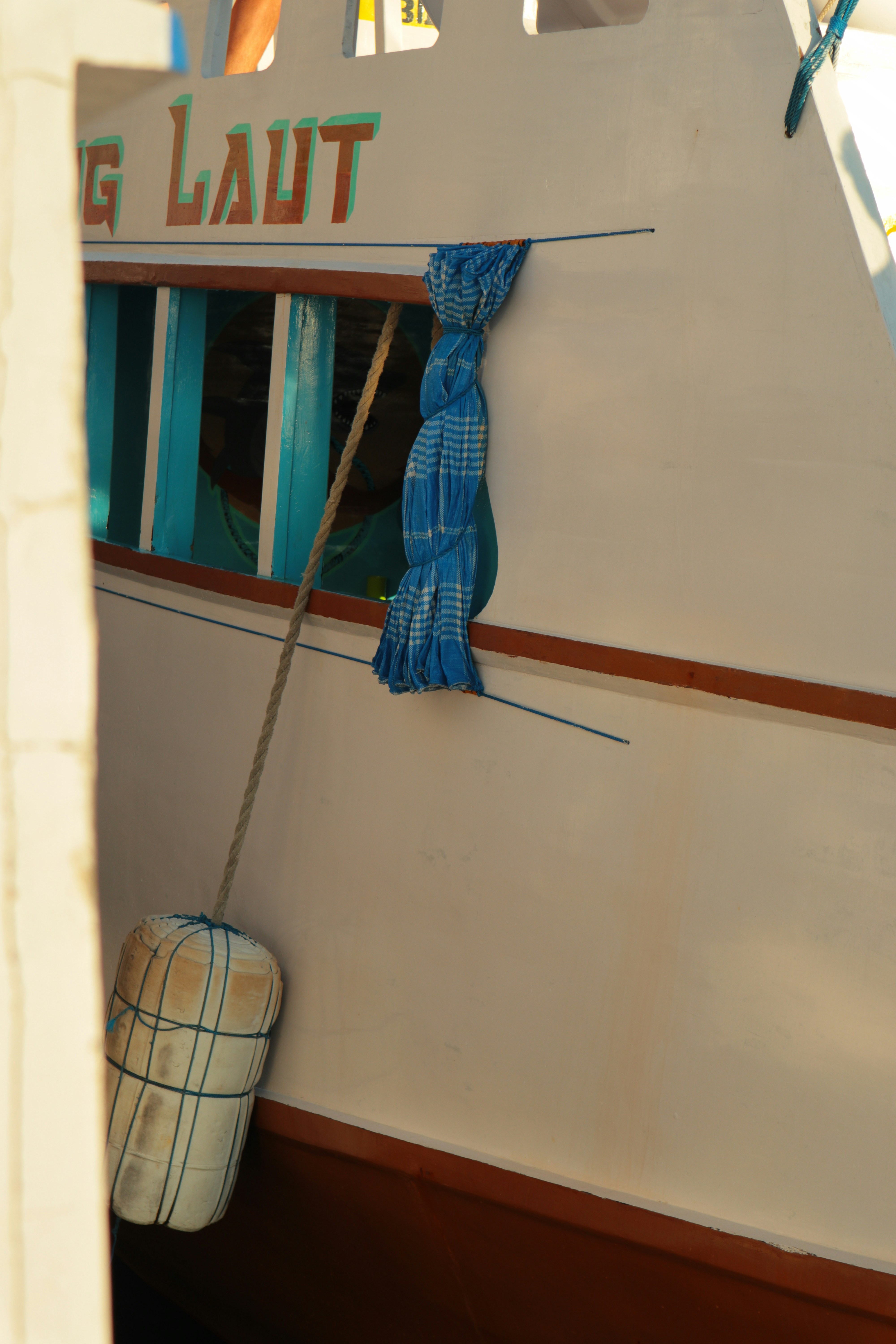 Blue rope and sailcloth on sunlit boat hull