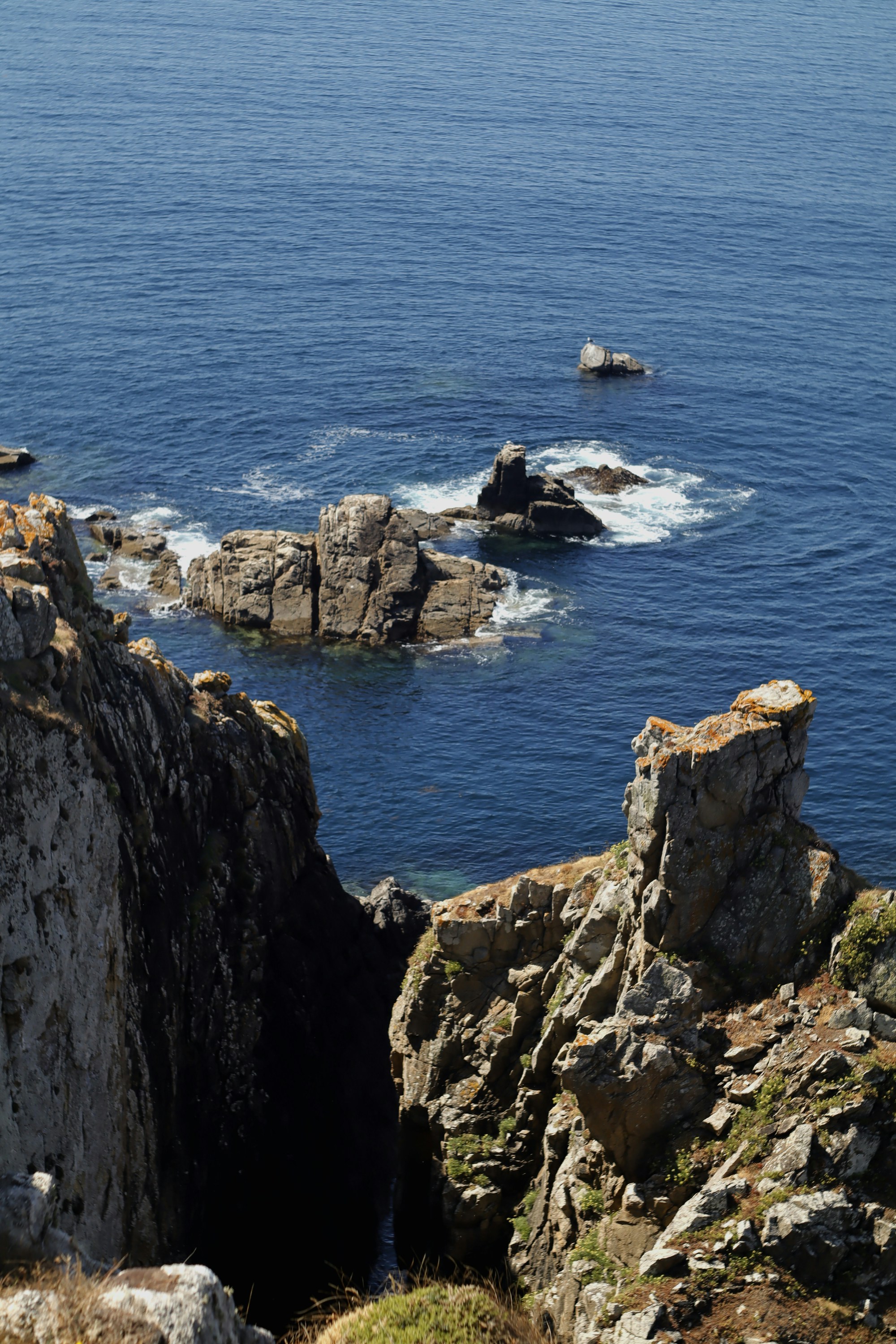 Cliffside Grotto: Sunlit Rocks Meeting the Deep Blue