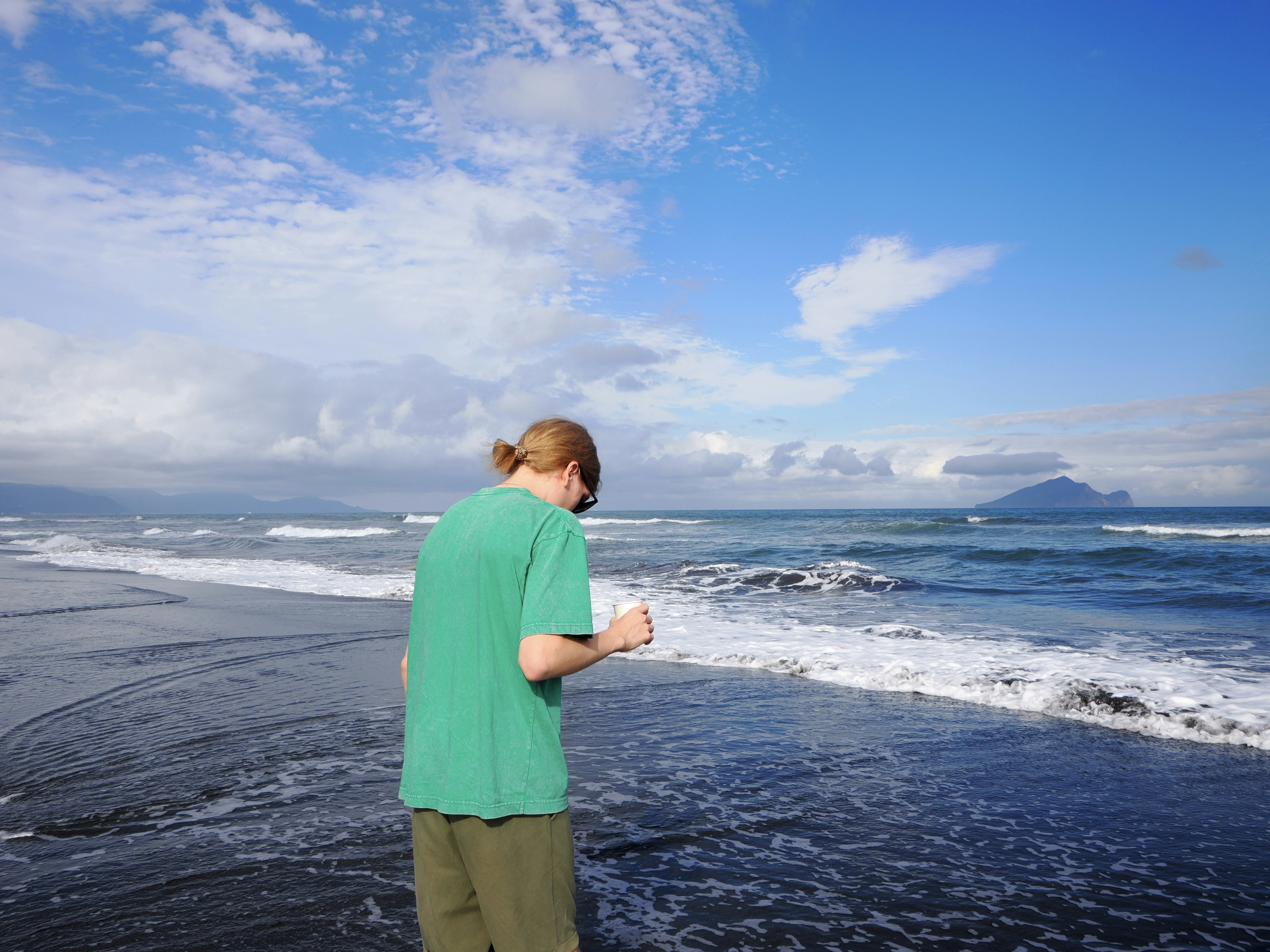Green-shirted wanderer by the restless shoreline