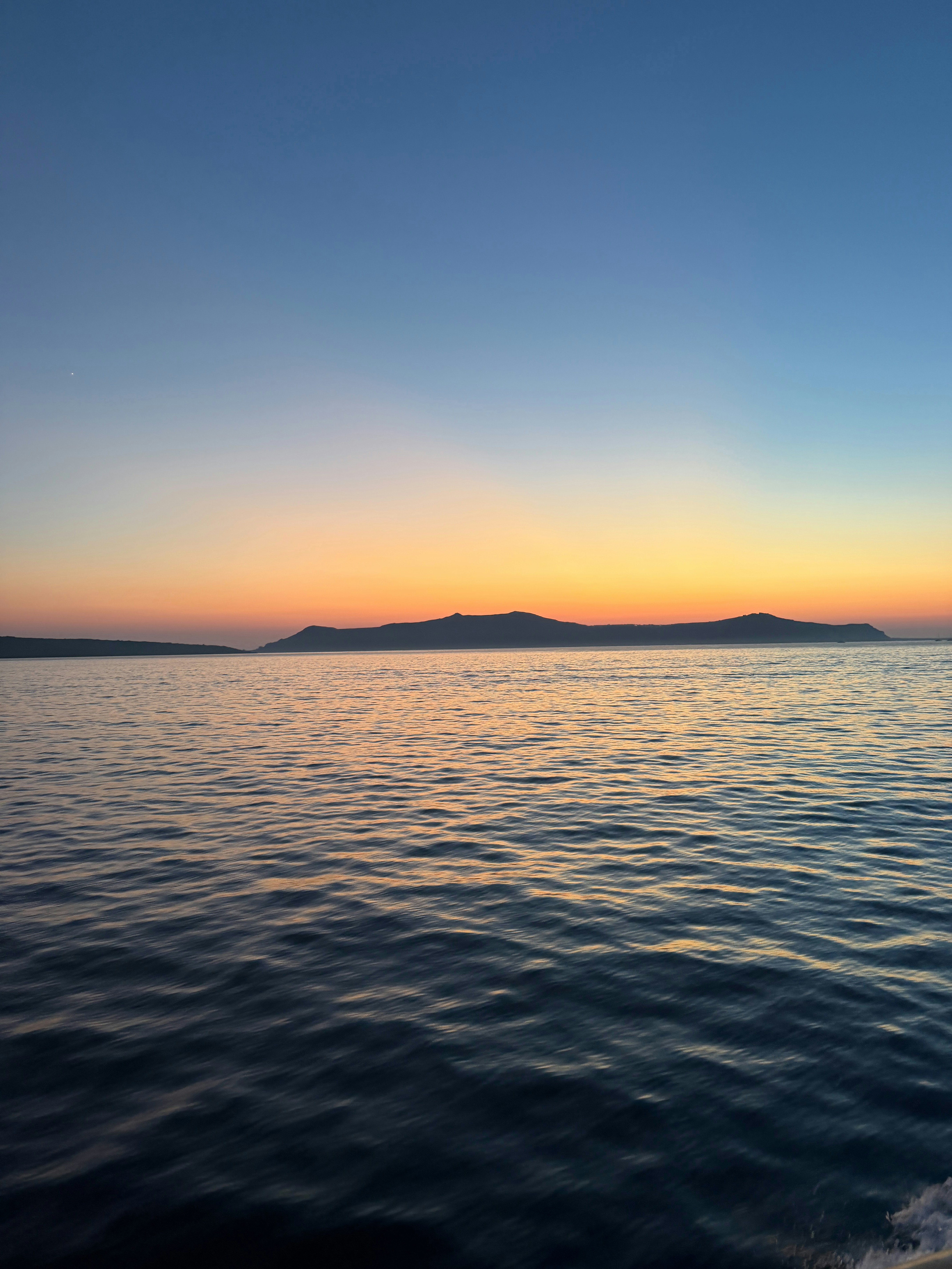 Horizon Bloom: Silhouetted Islands at Sunset over Calm Seas
