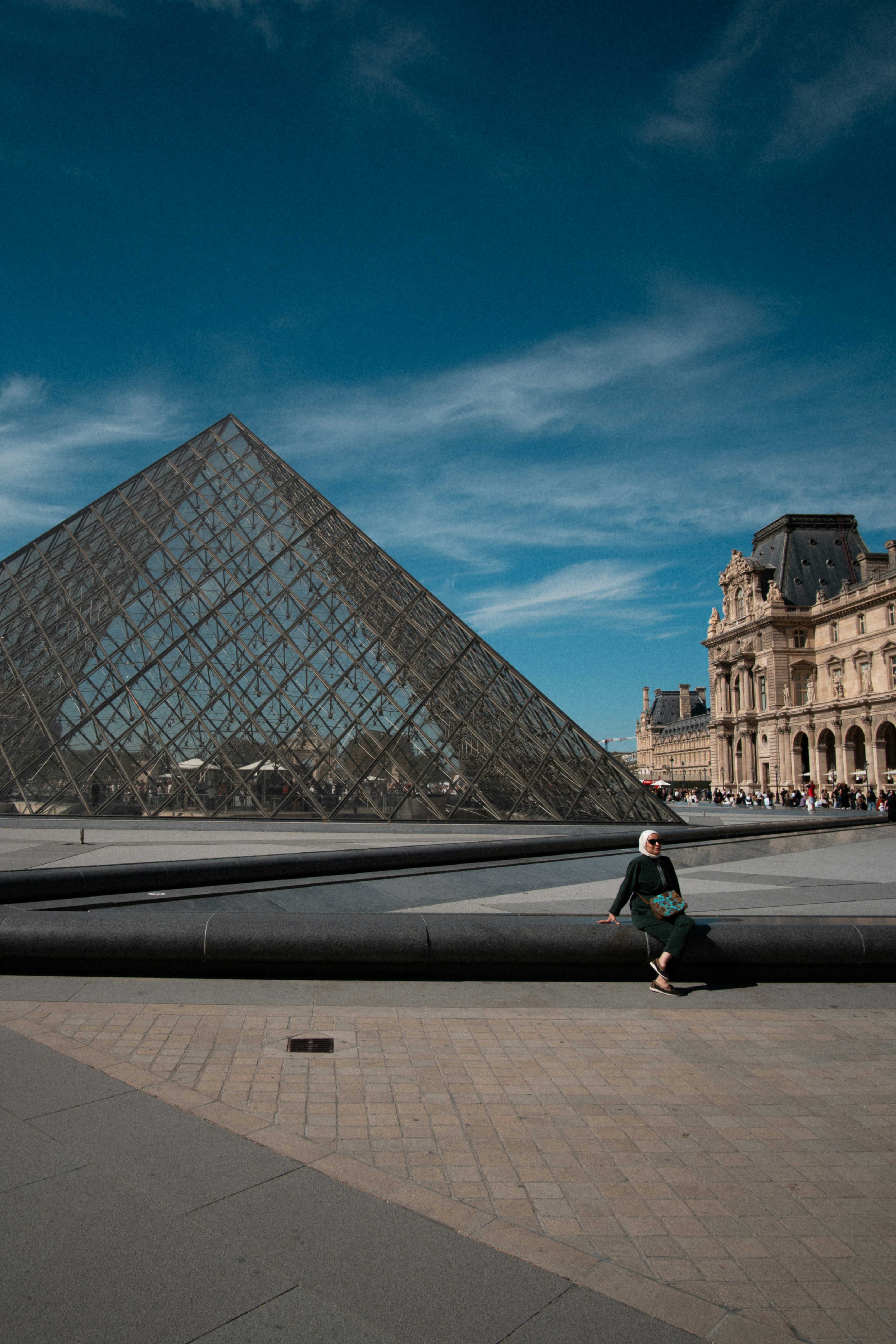 Glass Pyramid Under a Blue Sky with a Seated Figure