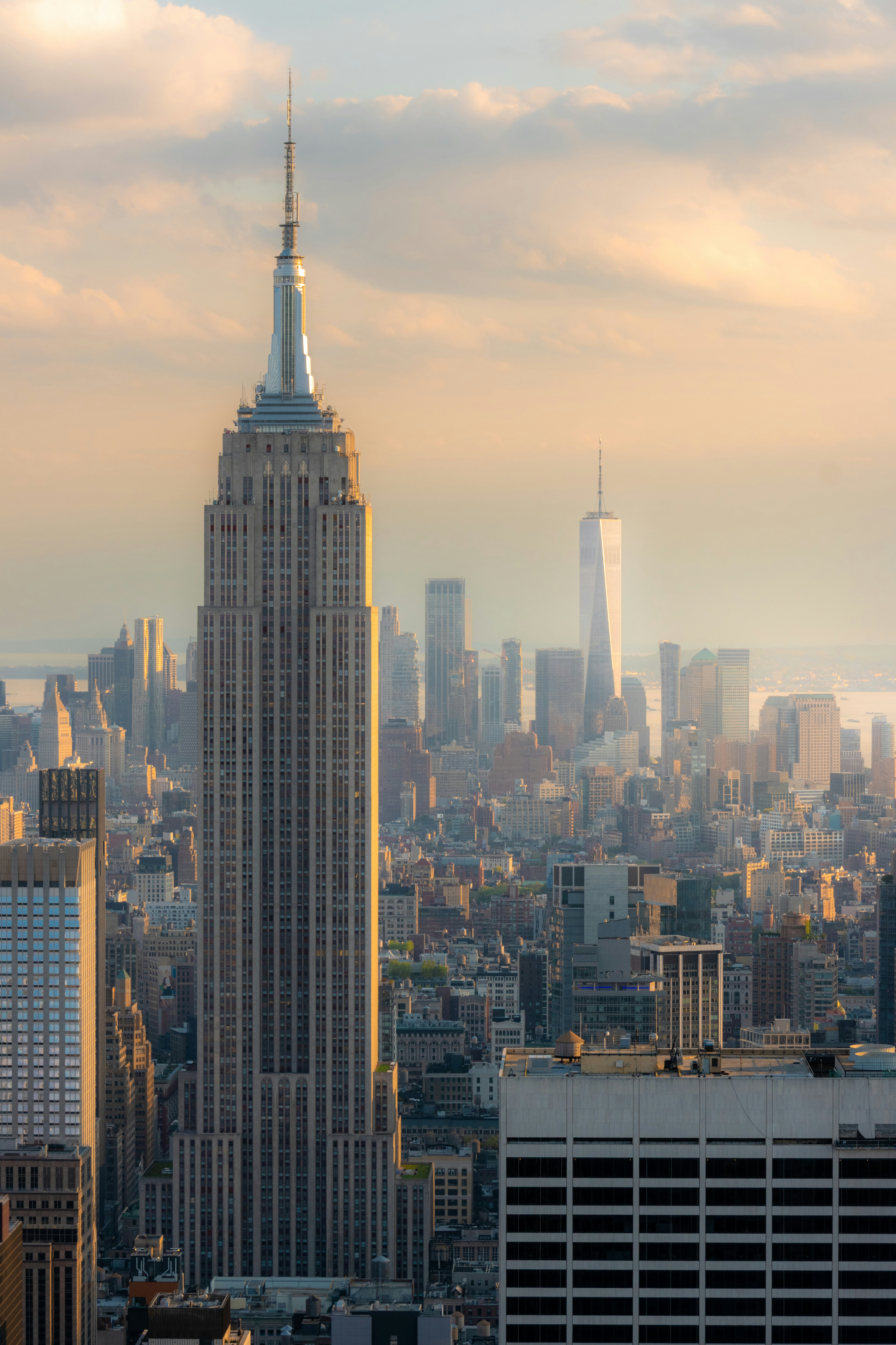 Golden-hour skyline with the Empire State Building dominating the foreground and the city fading into warm haze.