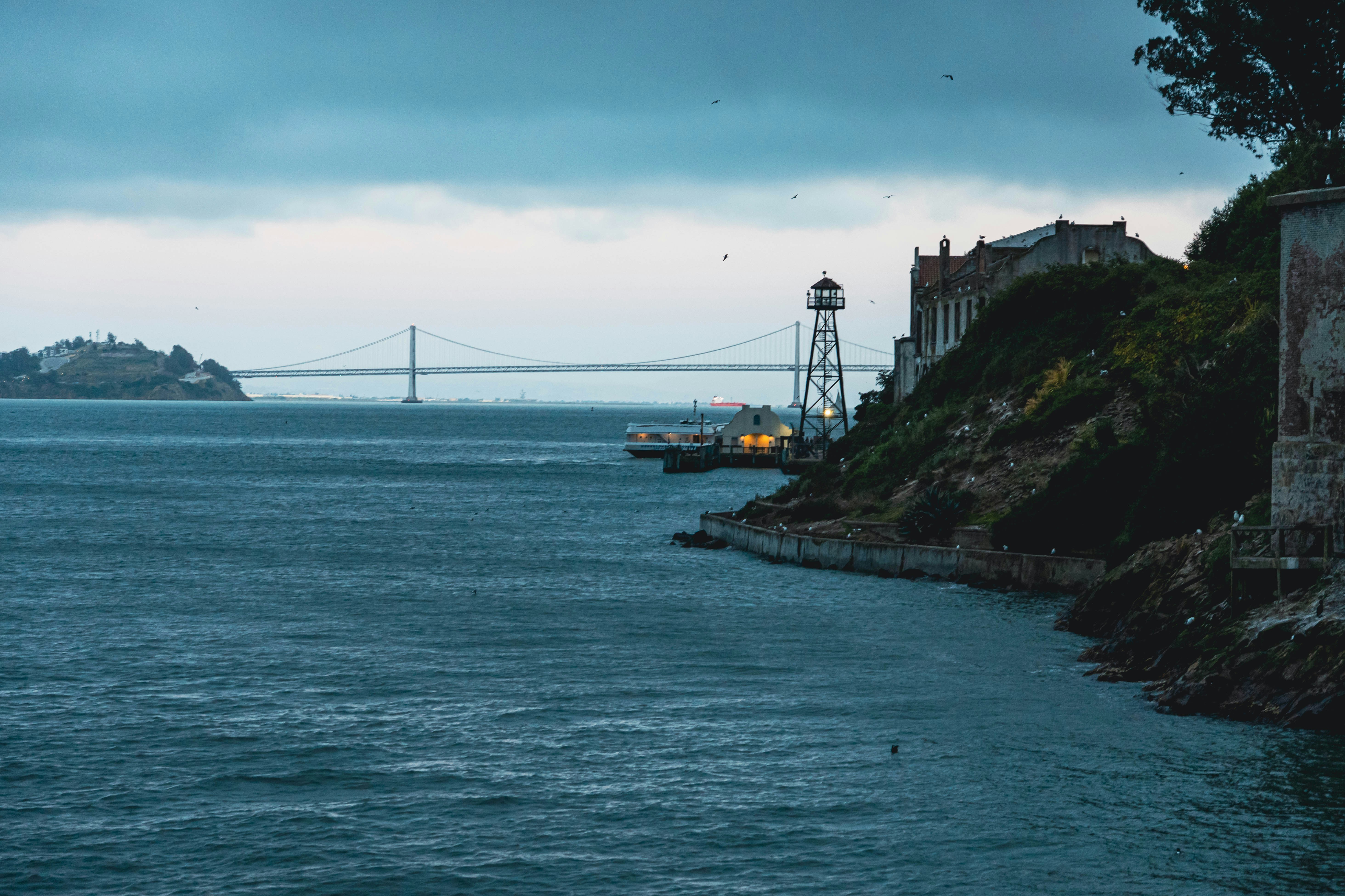 Coastal harbor and distant bridge under moody skies