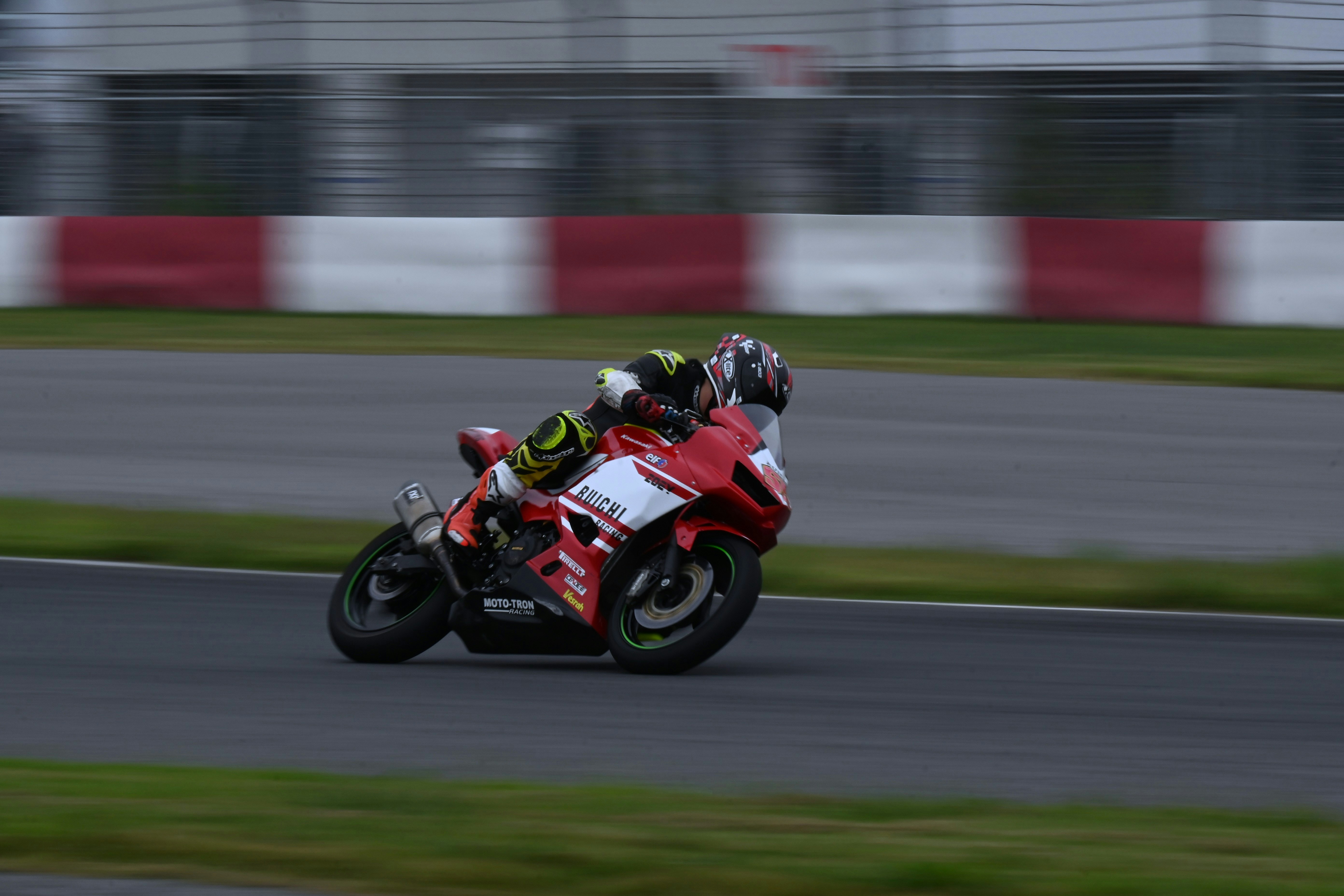 Leaned into the Turn: Red racer slices the track on a red-and-white barrier backdrop