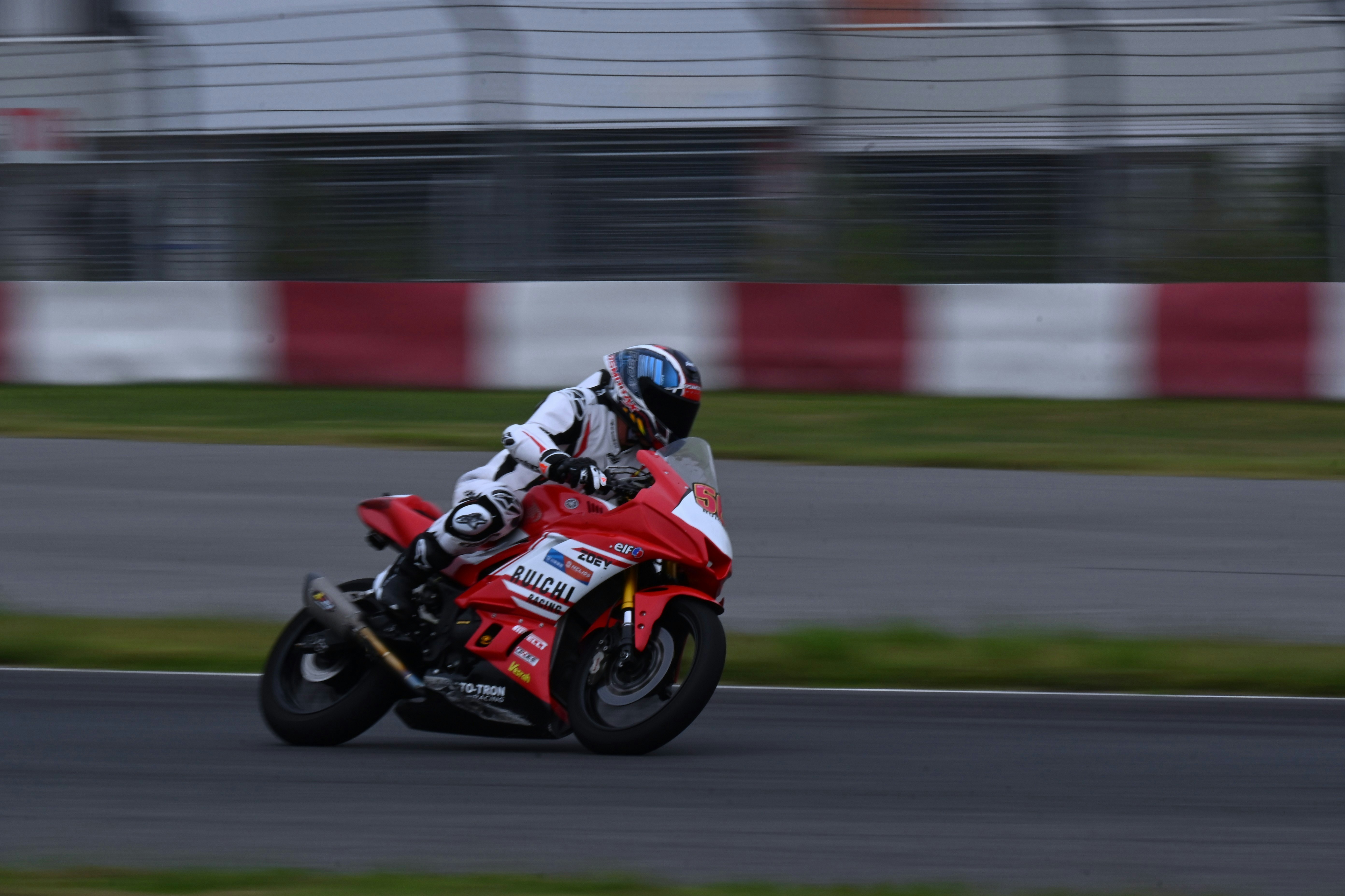 Rider in a Red Blur: Racing Through a Barrier-Striped Turn