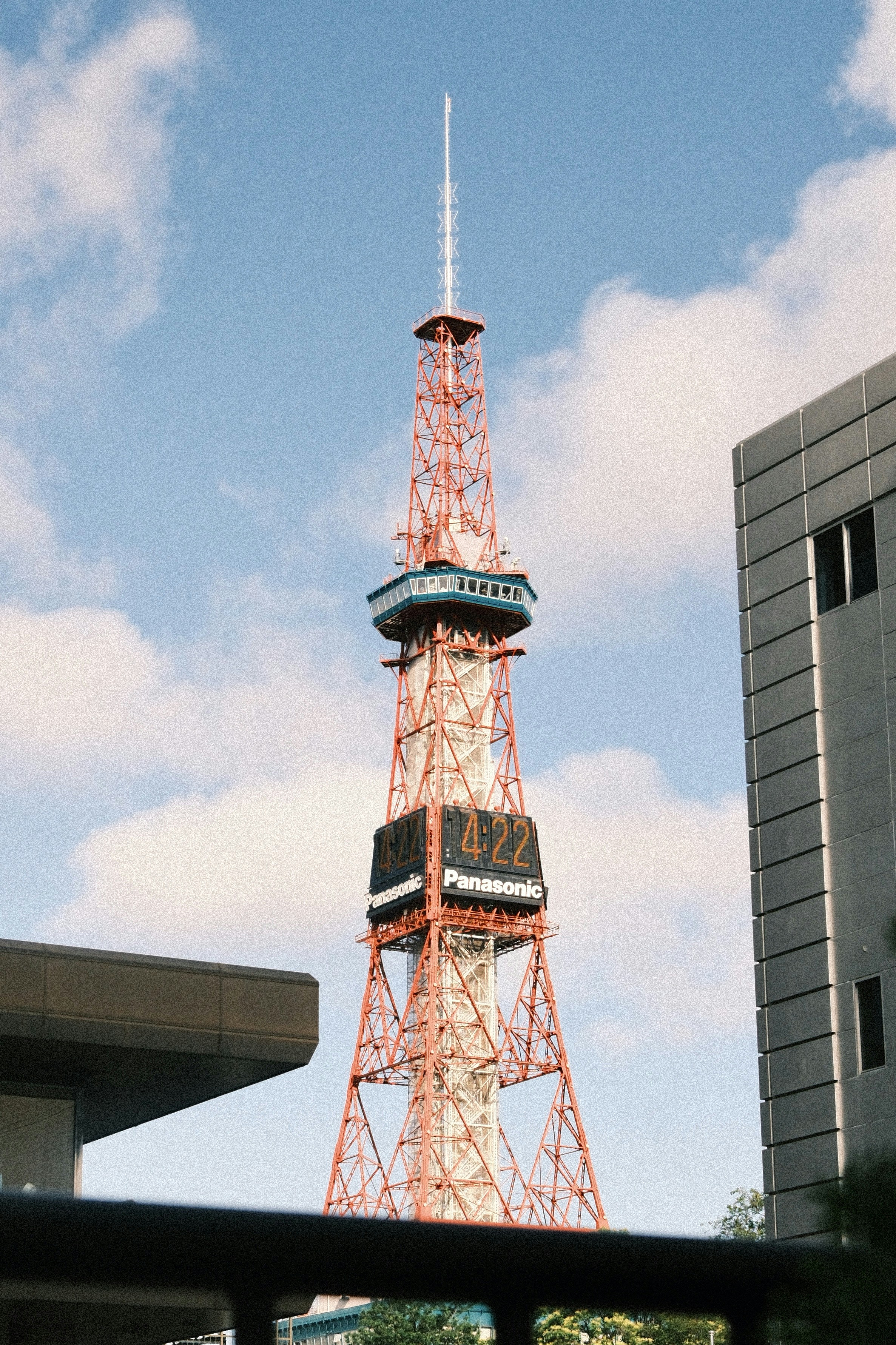 Skyward Signal: A Red-and-White Tower Pierces the City Sky