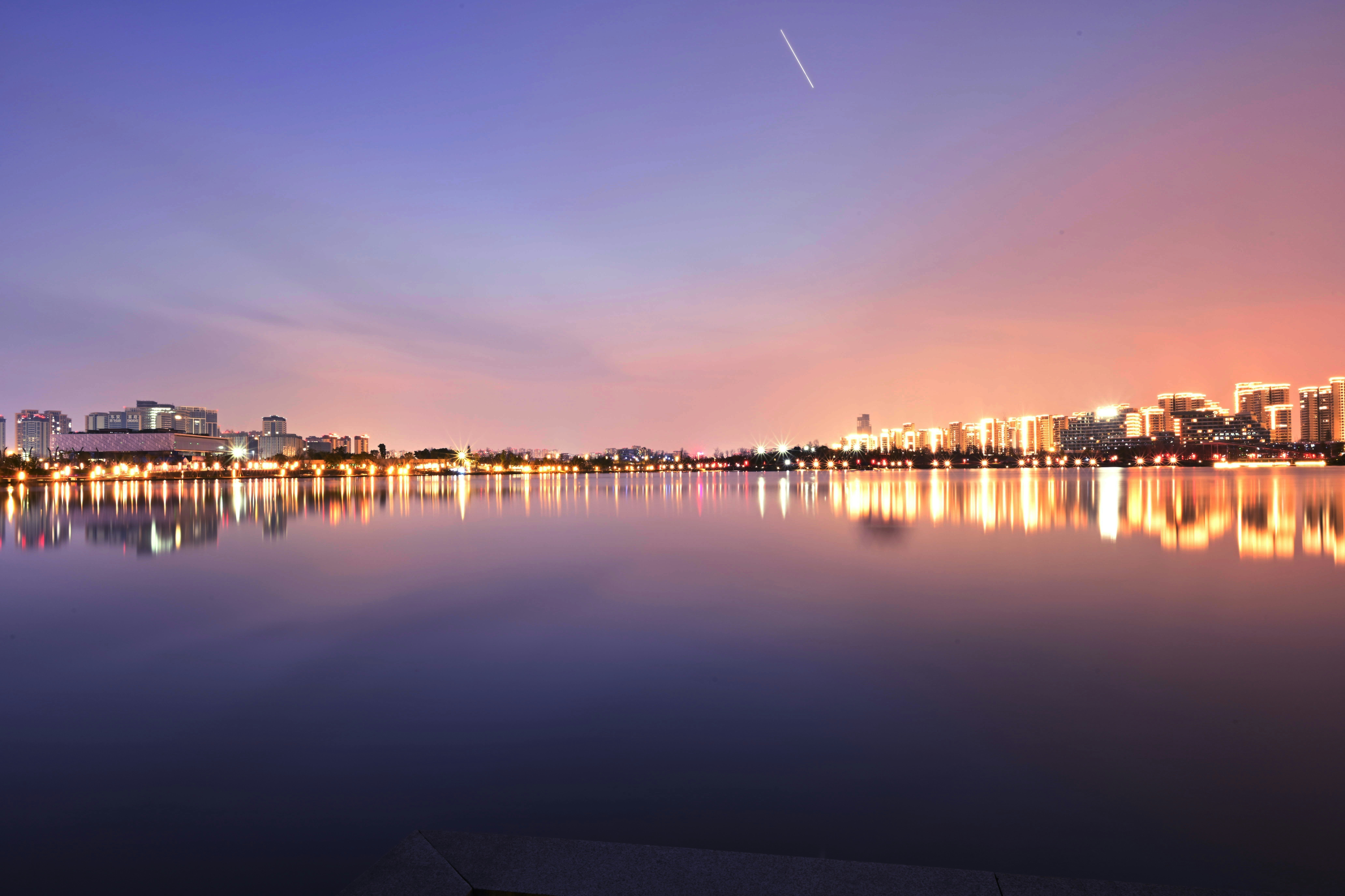 City Lights Mirror: Twilight Waterfront Over Calm Waters