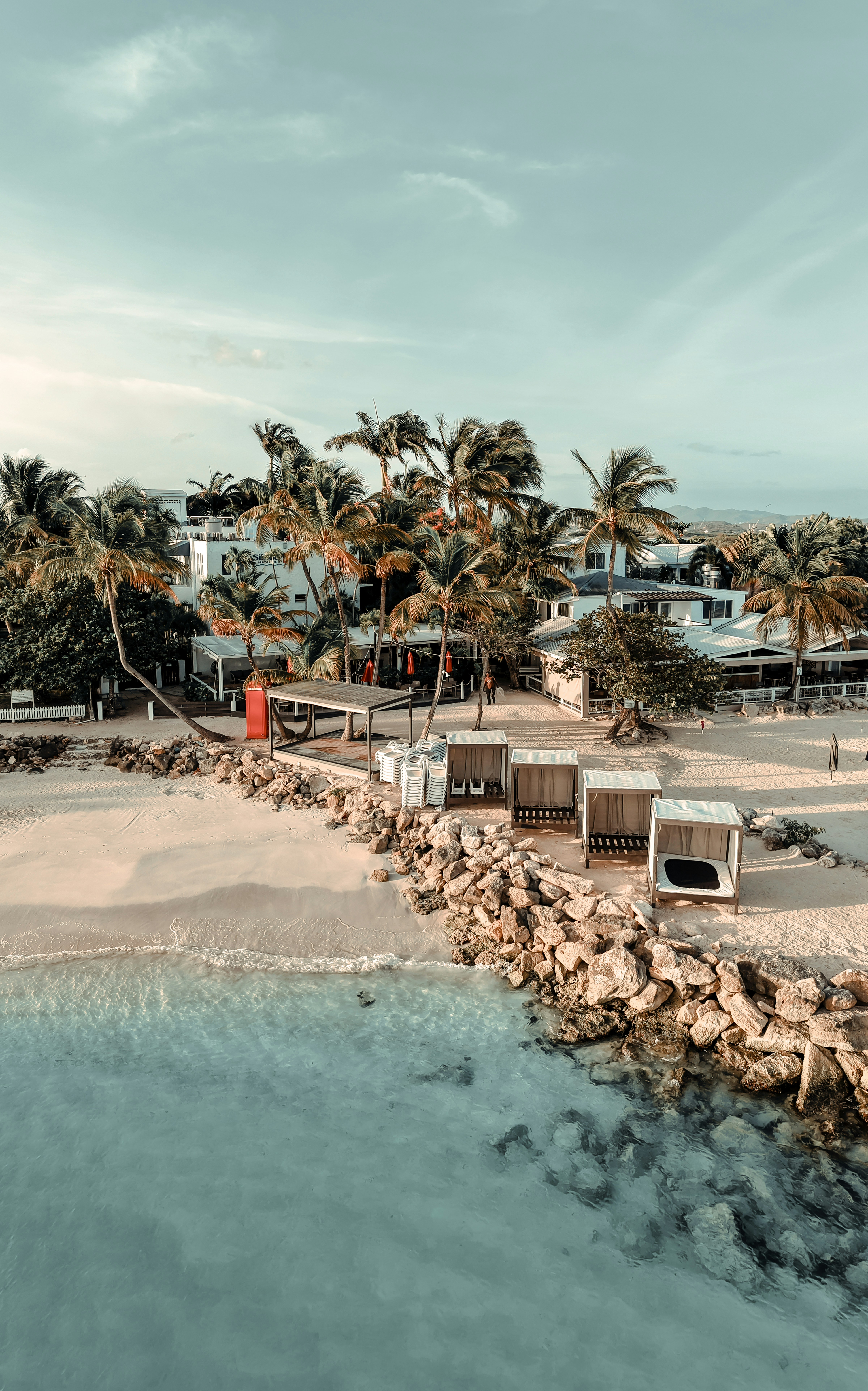 Palm-studded beachfront village from a sunlit drone view