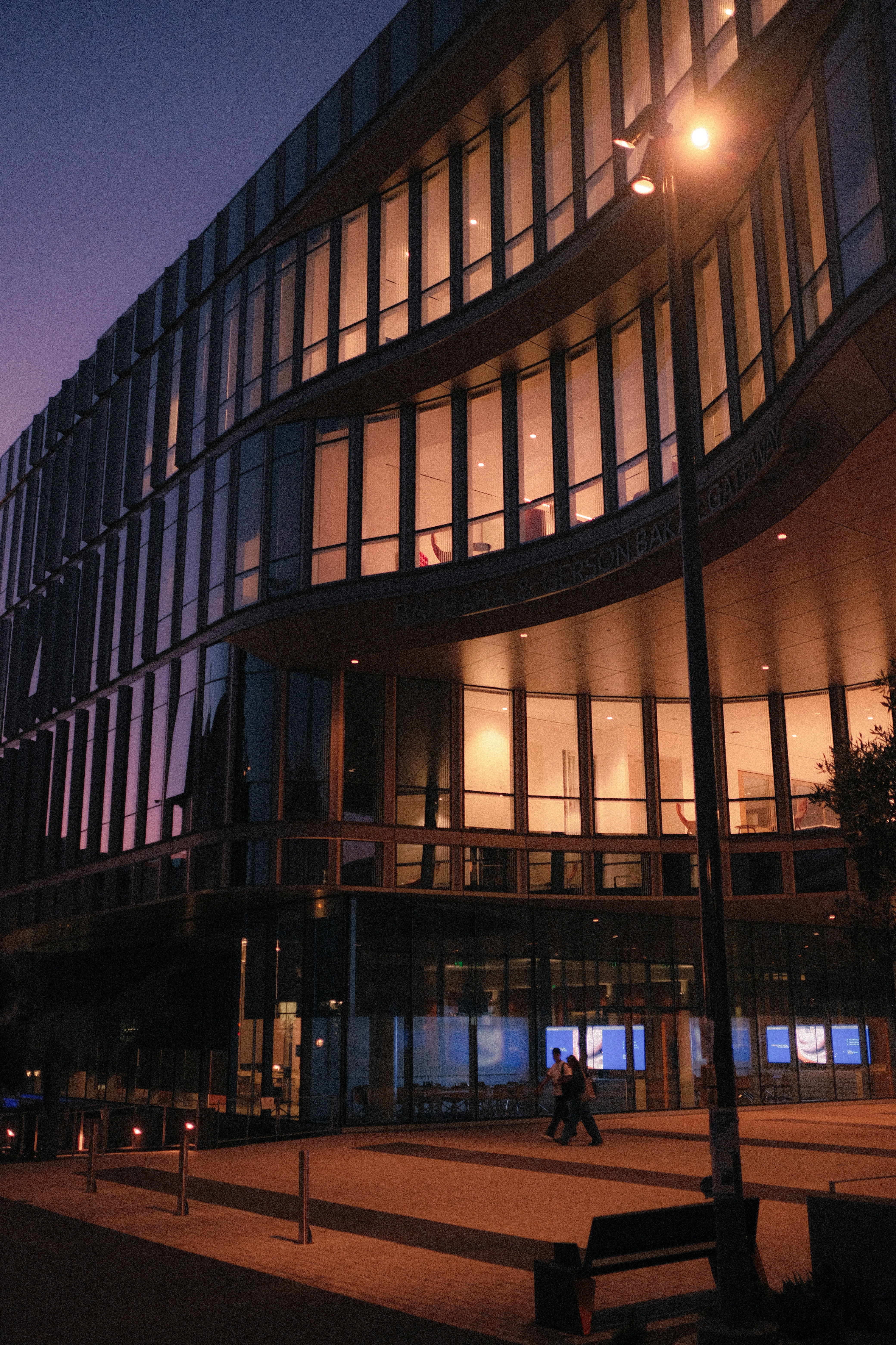 Glass Facade at Dusk: Illuminated Atrium Amid Modern Curves